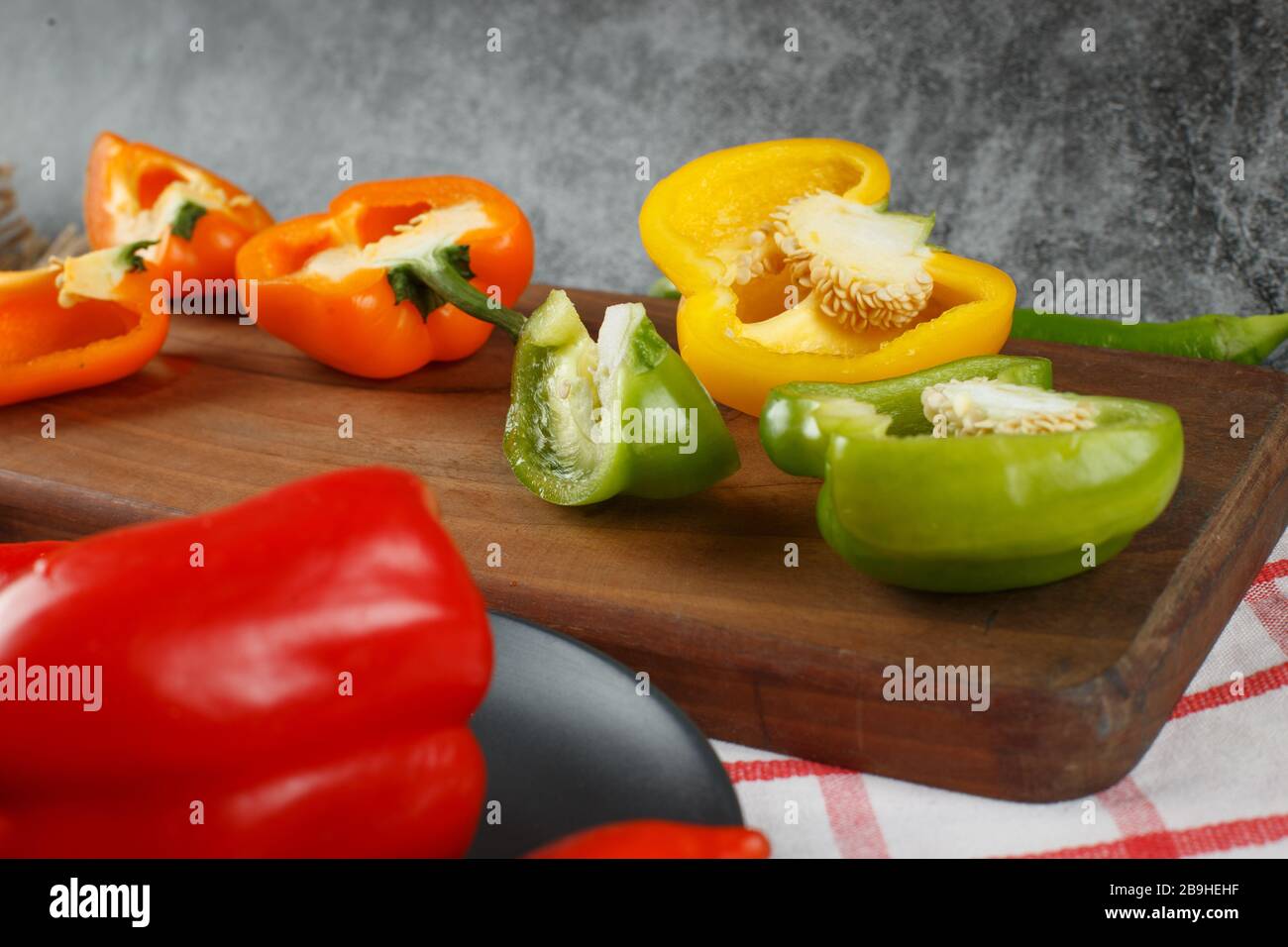 Color bell peppers cut into pieces on a wooden board Stock Photo - Alamy
