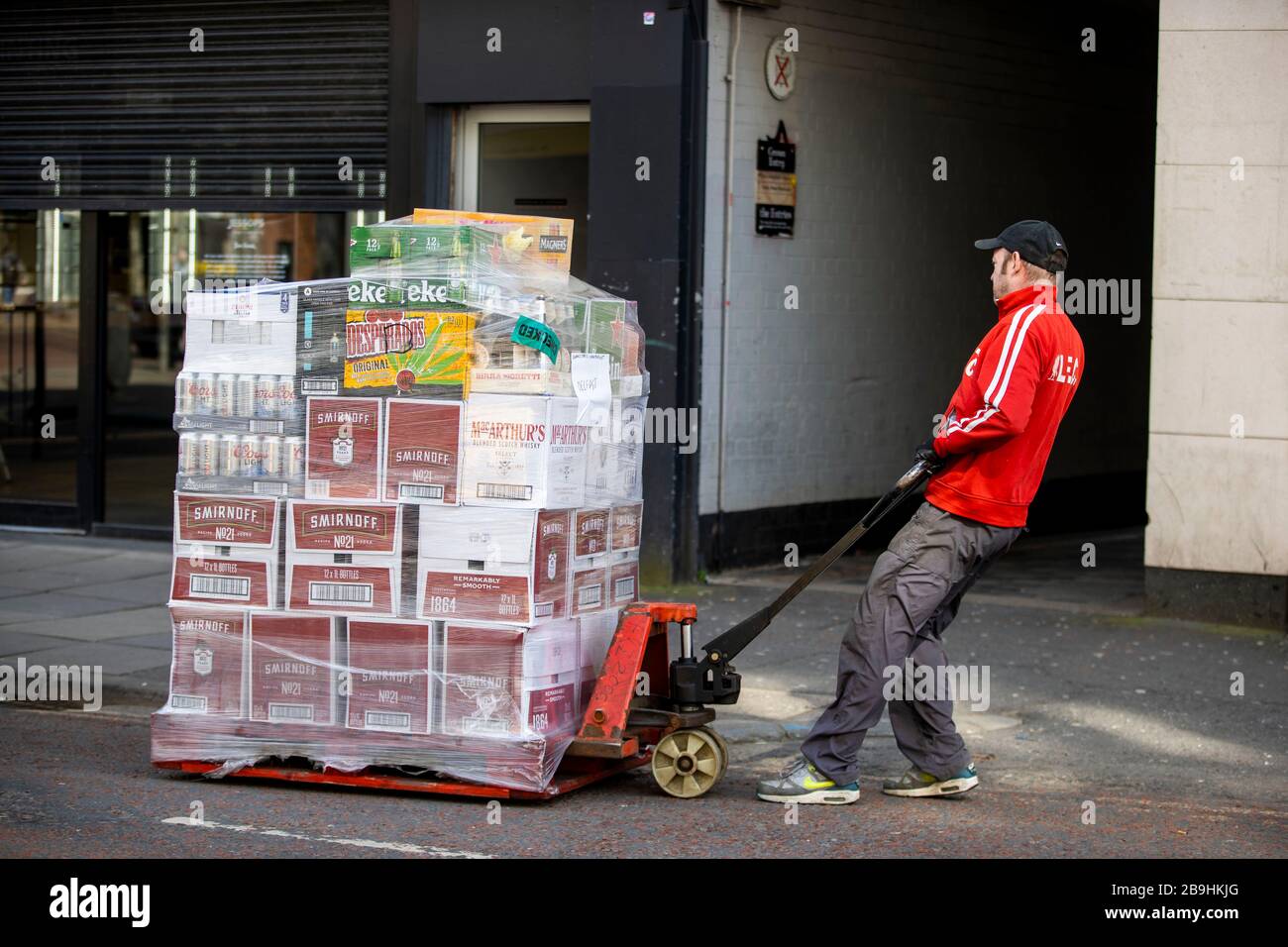 A delivery man pulls a trolley of alcohol through Belfast Stock Photo ...