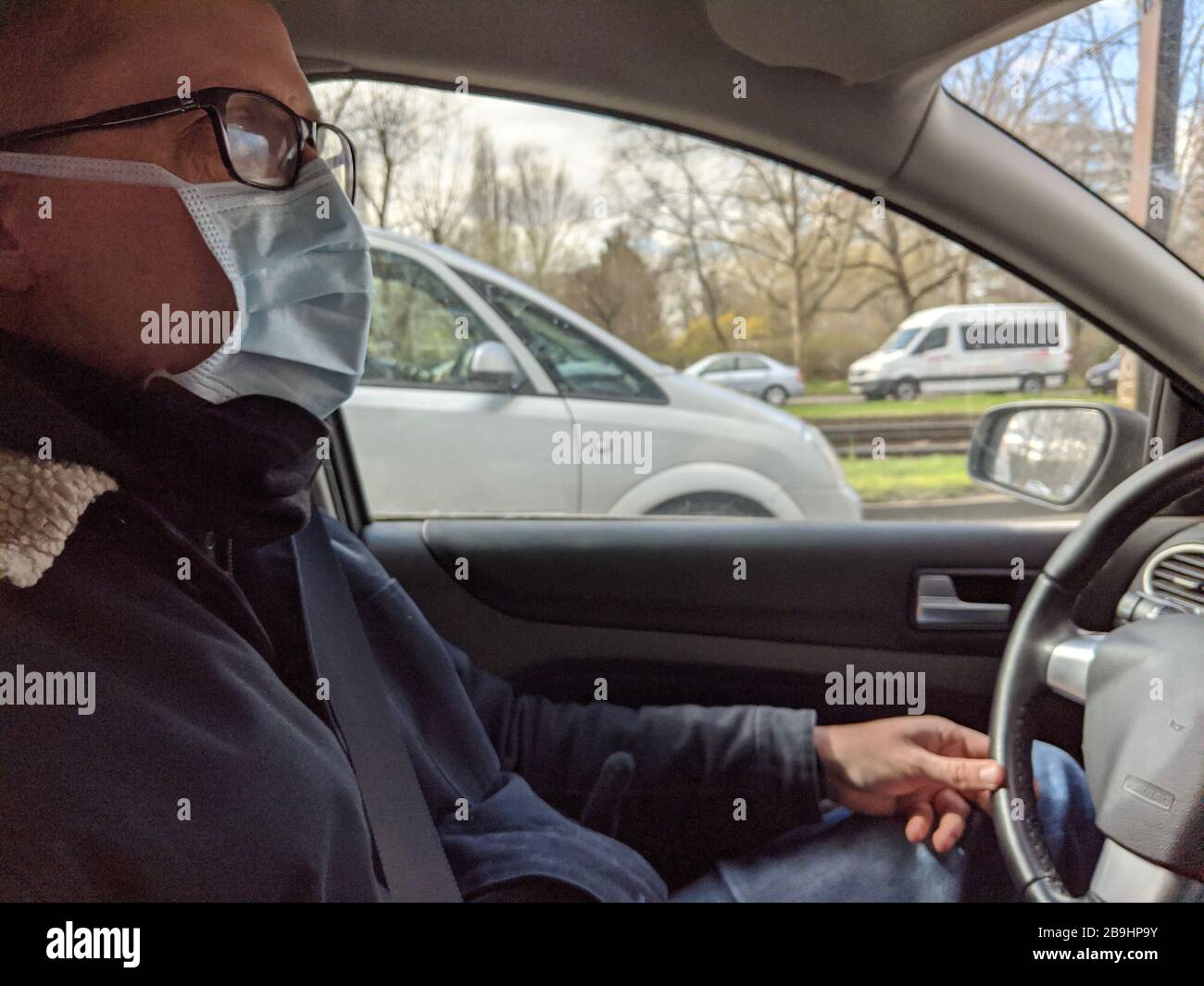 Man with face mask driving in car through city Stock Photo - Alamy