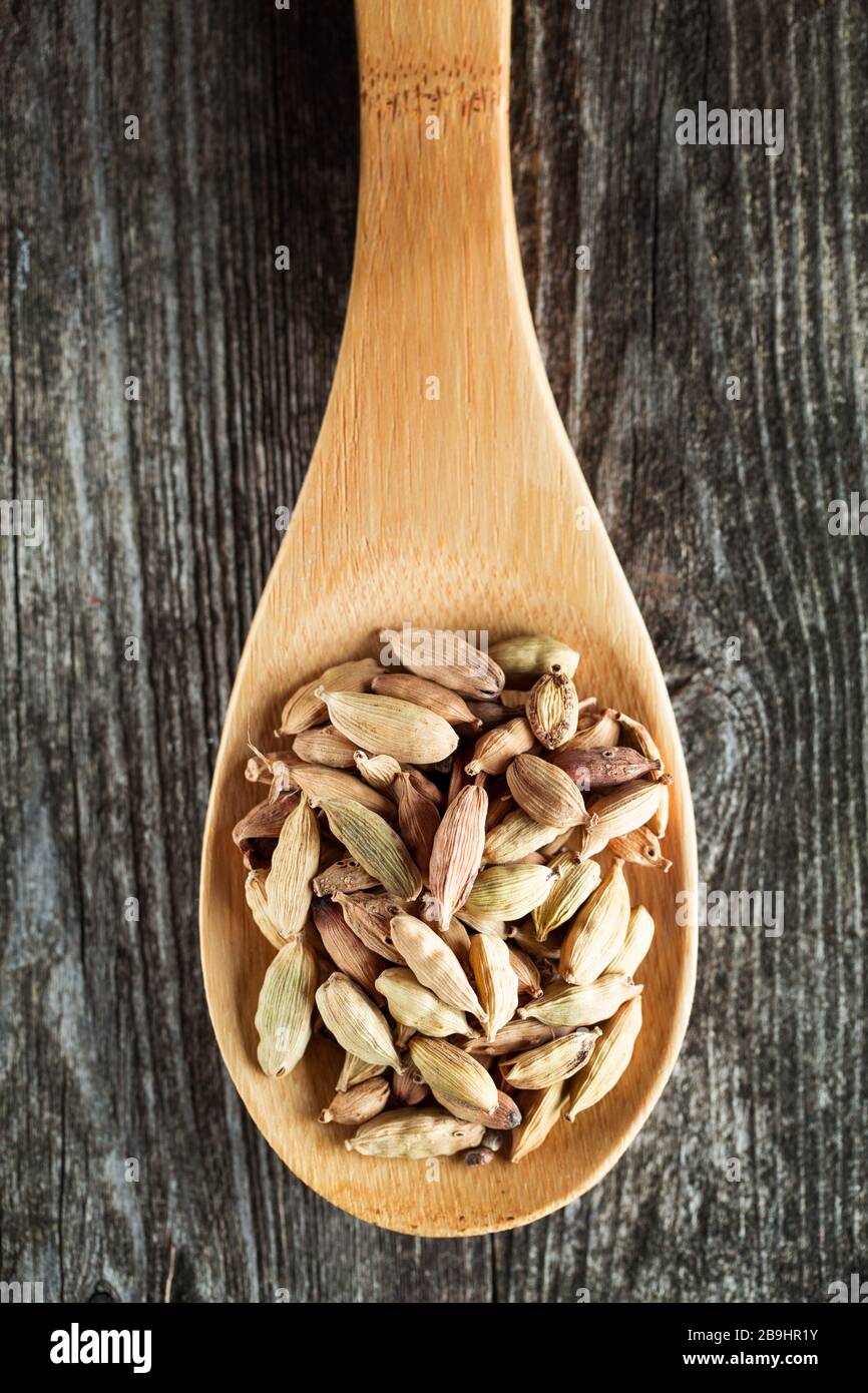 Raw organic cardamom spice pods on wooden spoon on rustic background ...