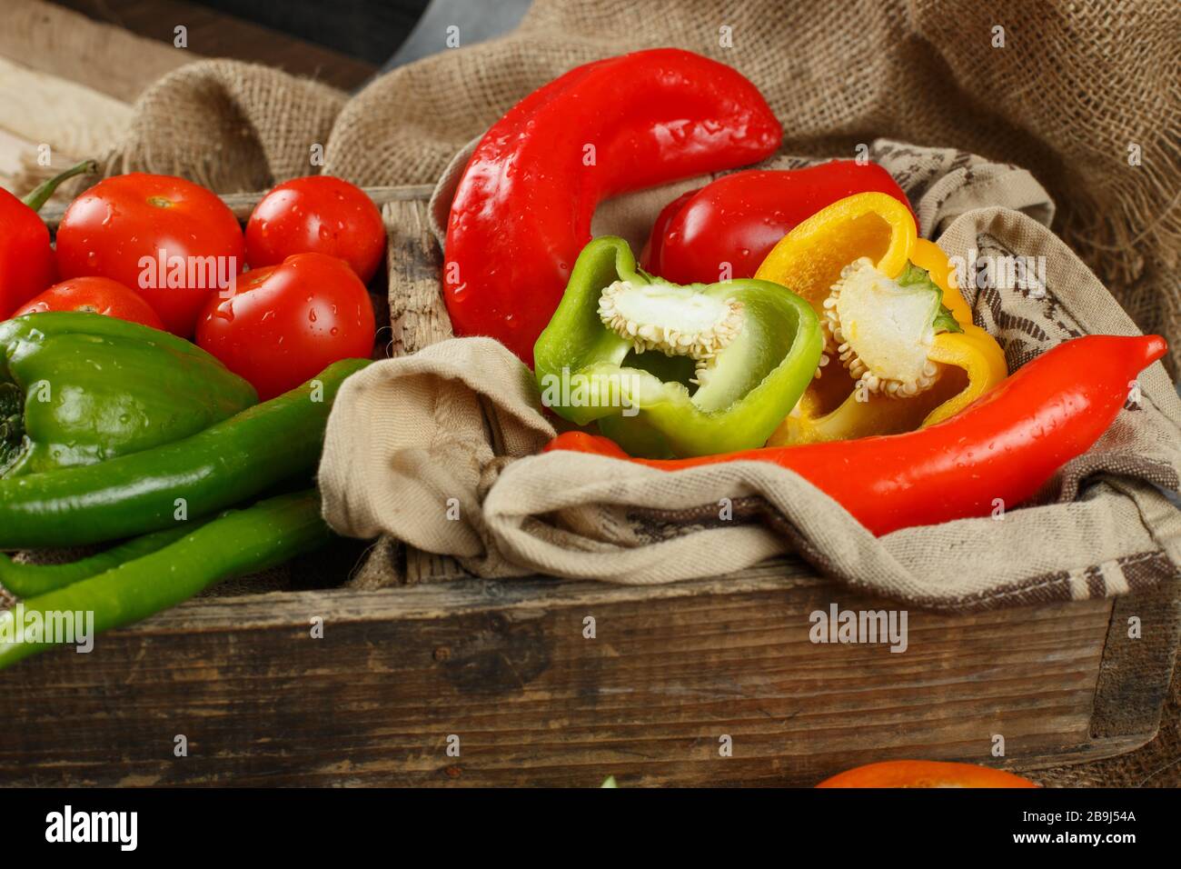 Mixed peppers in a wooden tray on a rustic towel Stock Photo - Alamy