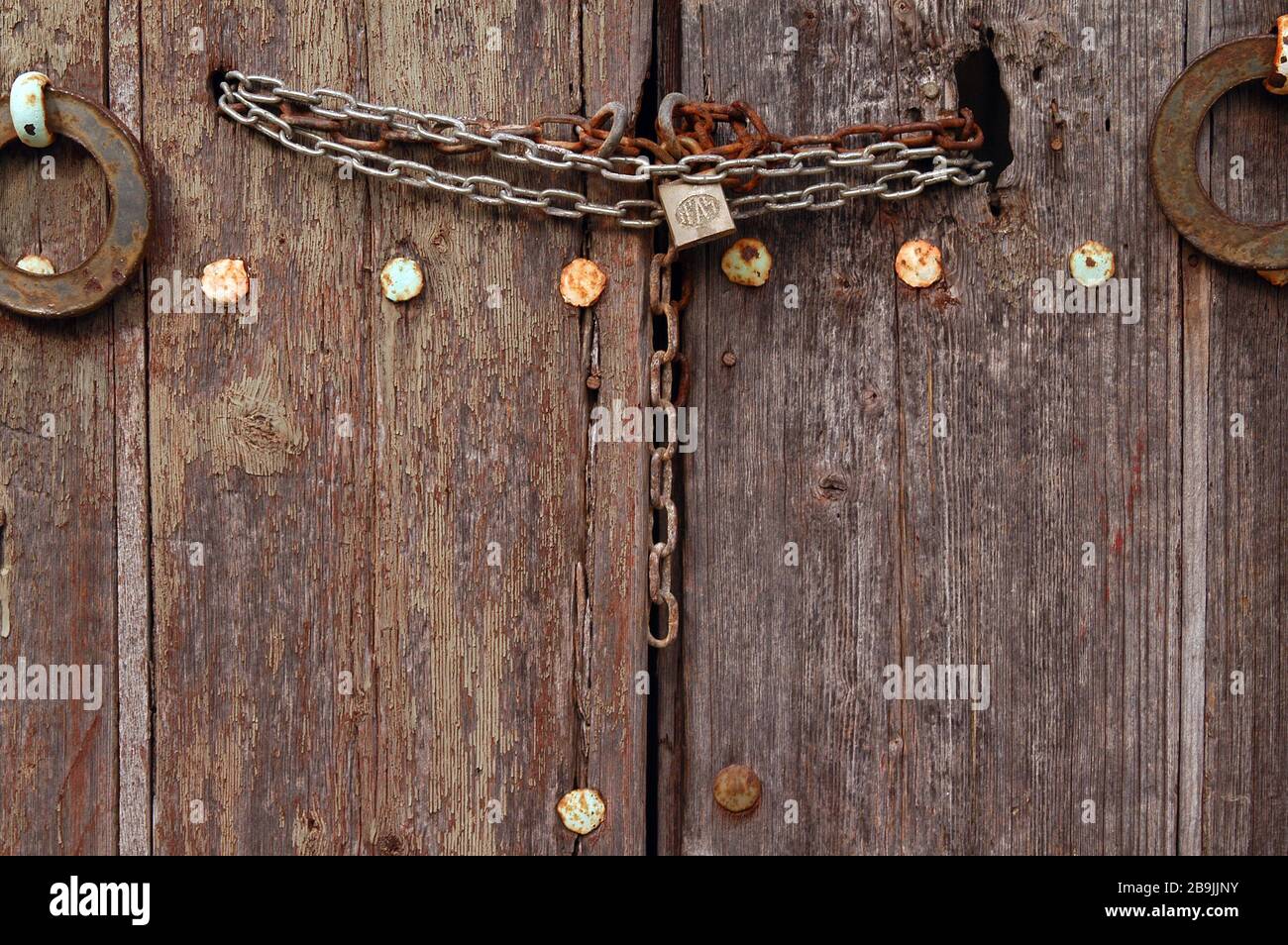 Chains and padlock through an key hole of an old wooden door with metal ...