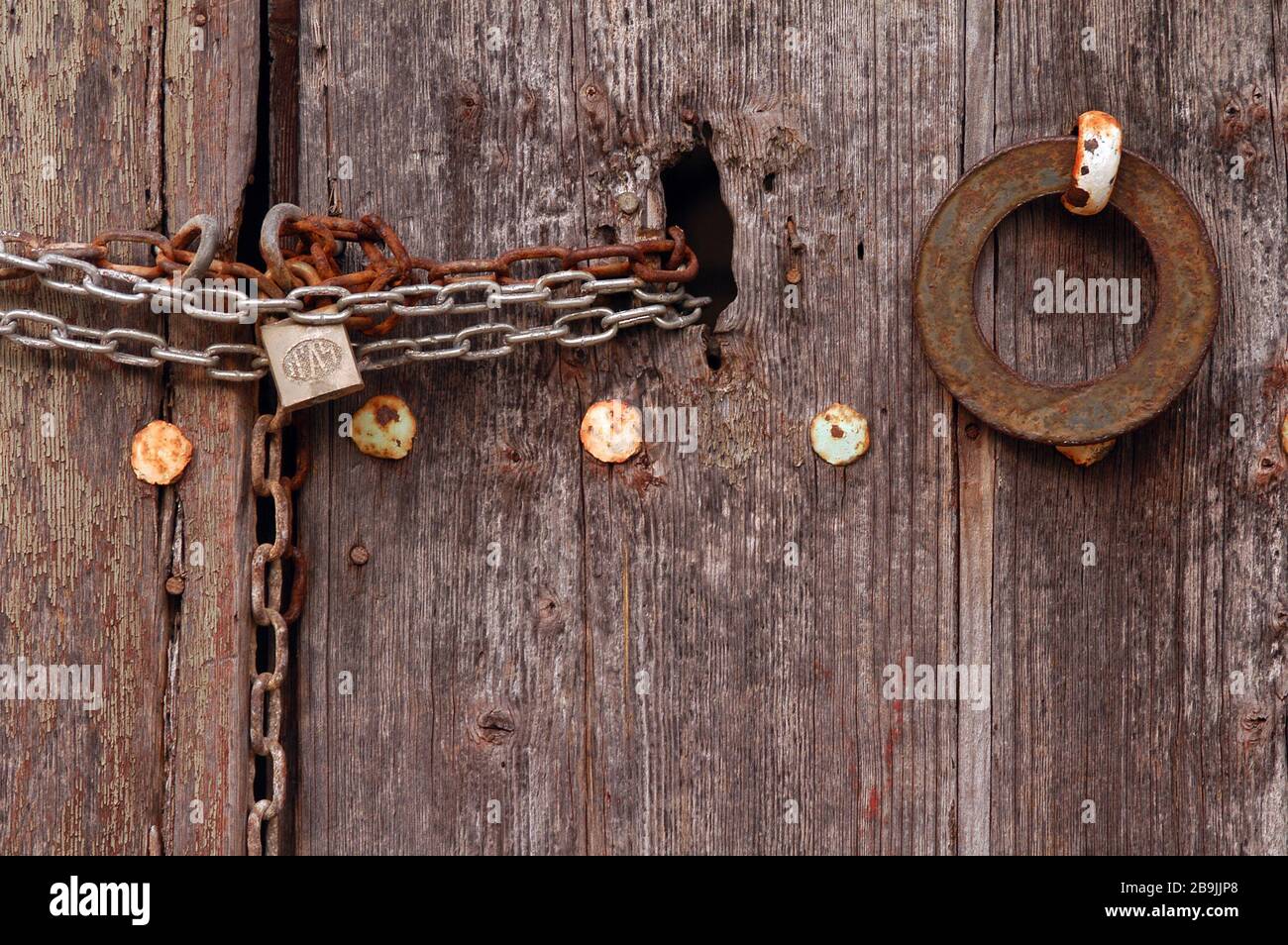 Chains and padlock through an key hole of an old wooden door with metal ...
