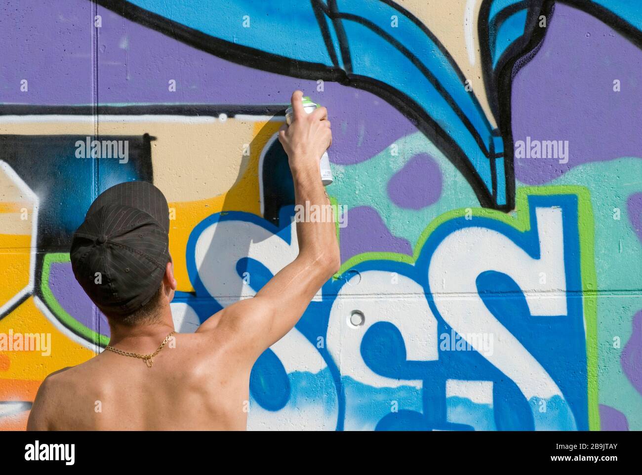 young man spraying graffiti on wall Stock Photo - Alamy