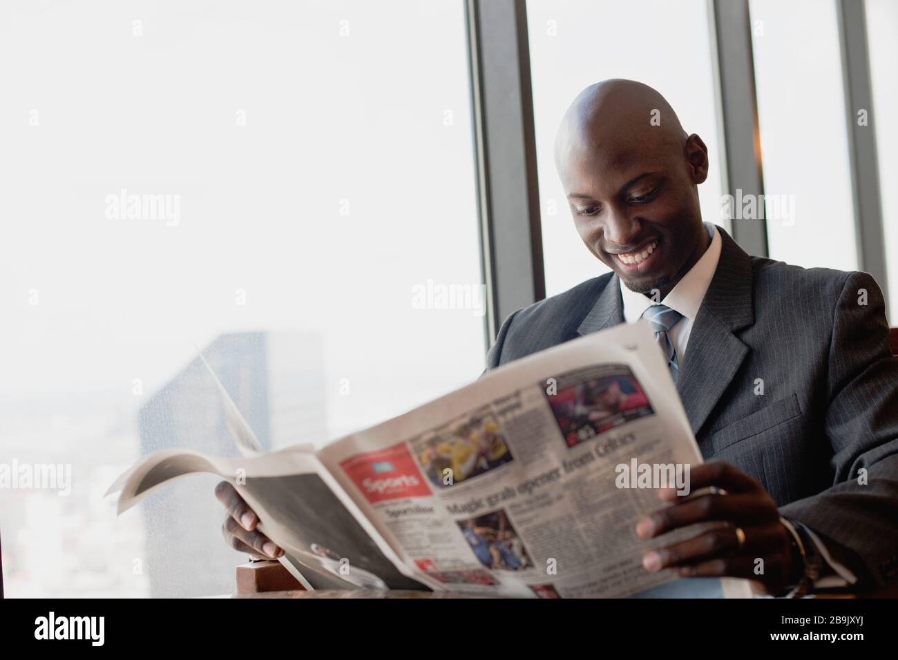 Man reading newspaper beside window Stock Photo - Alamy