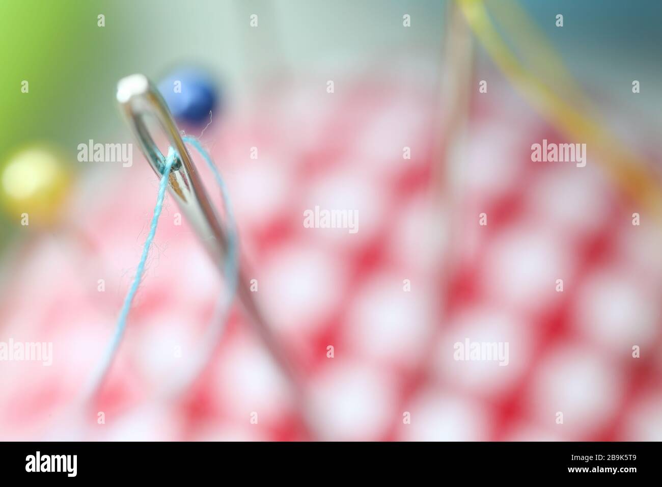 Needle eye with piece of blue thread stick out of pincushion Stock ...