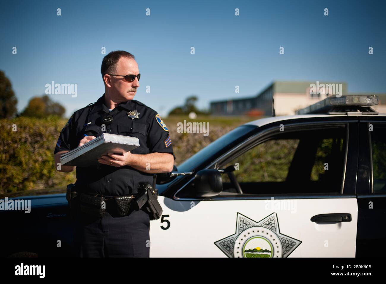 An American police officer writing notes next to his patrol car Stock ...