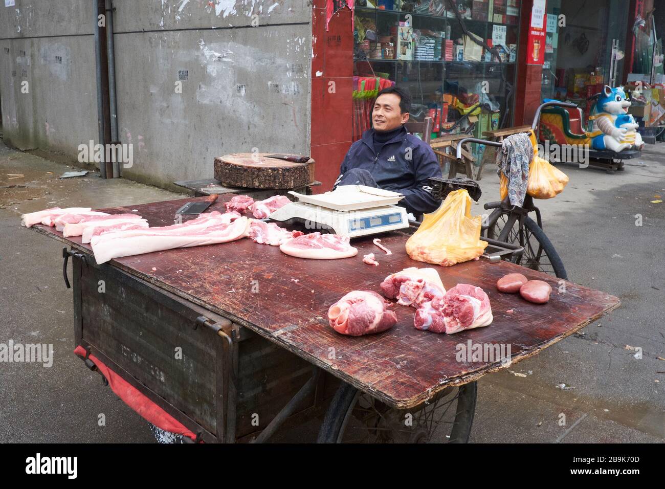 A butcher selling meat on the street in the Chinese city of Huangshi ...
