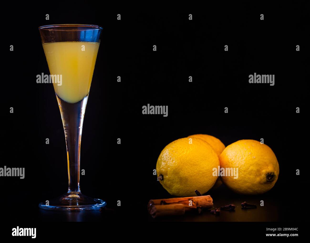Limoncello in elegant liquor glass with lemon, cinnamon and cloves on ...