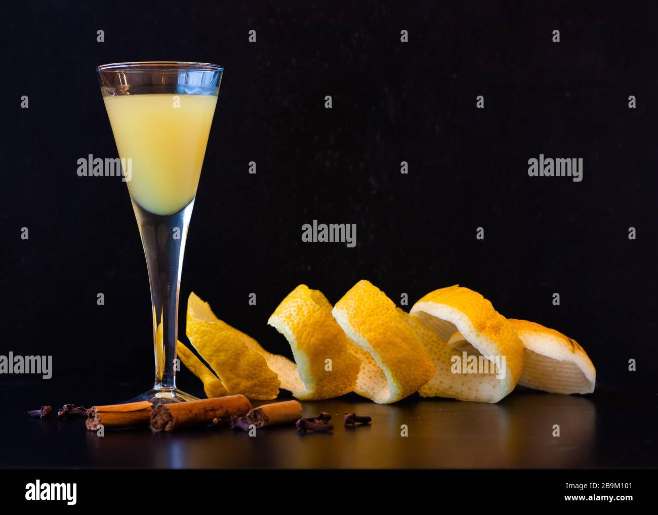 Limoncello in elegant liquor glass with lemon zest, cinnamon and cloves ...