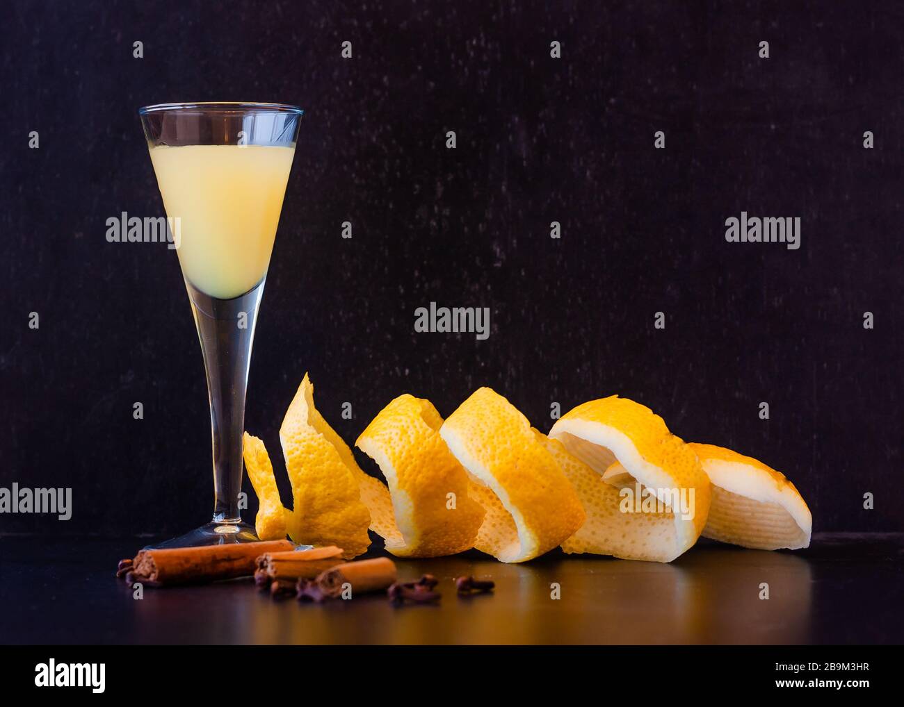 Limoncello in elegant liquor glass with lemon zest, cinnamon and cloves ...