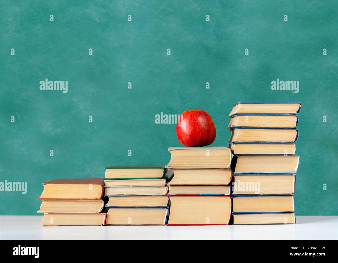 Back To School Pile Of Books And Red Apple With Empty Green School