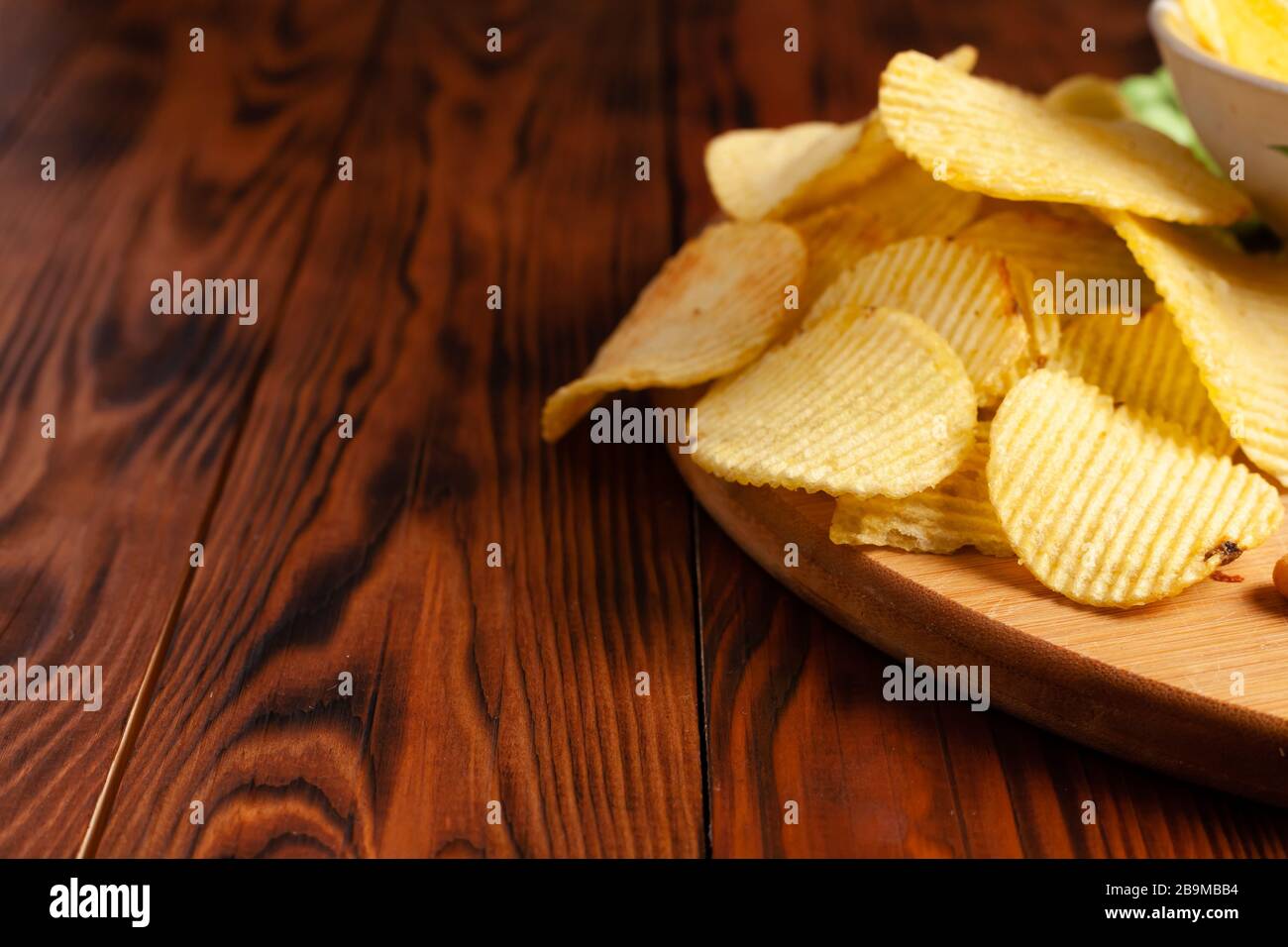 Assorted dry snacks on a wooden board. Chips, peanuts, croutons, wasabi ...