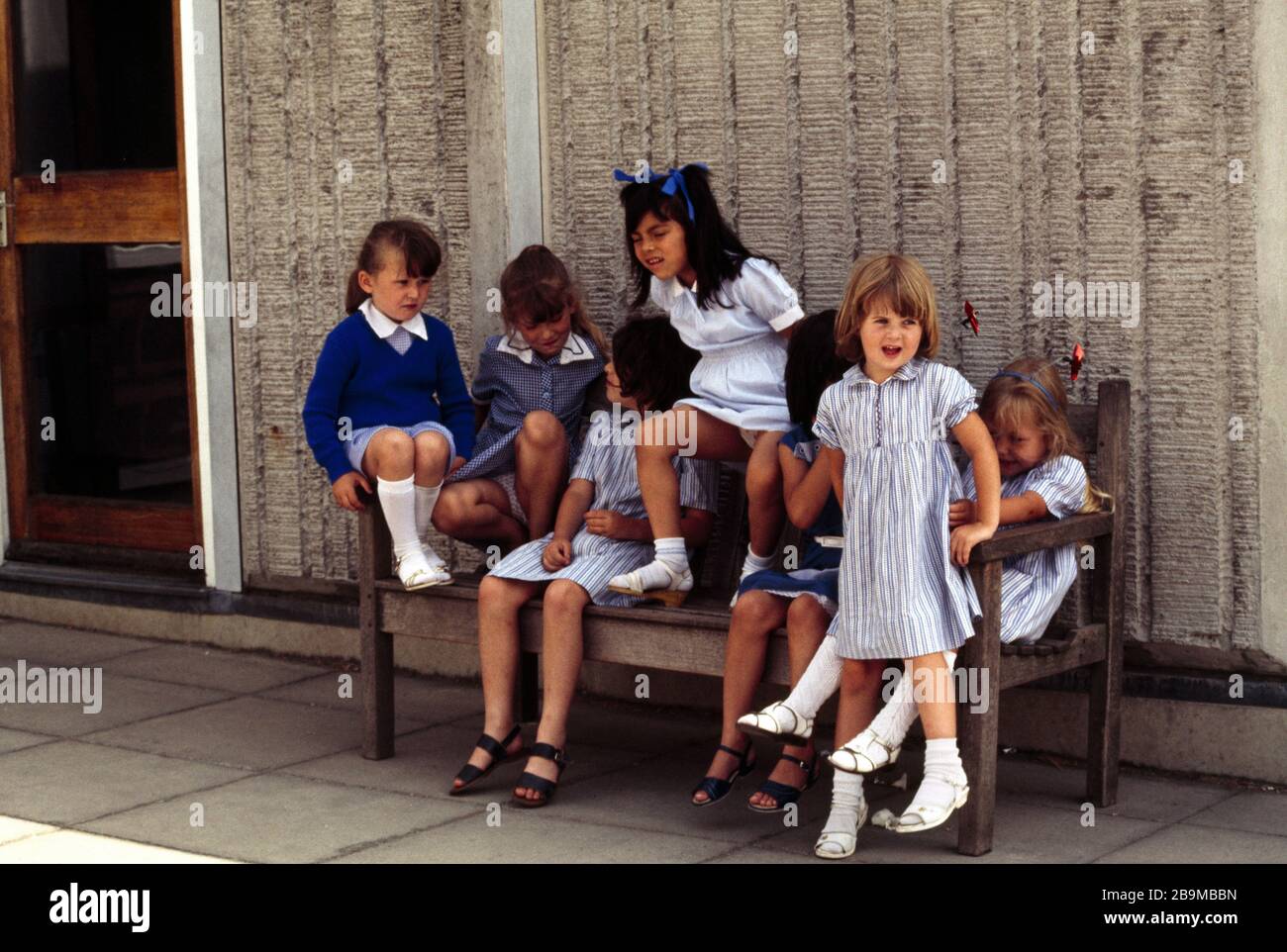 School Girls Sitting On Bench In Playground Uniform Stock Photo - Alamy