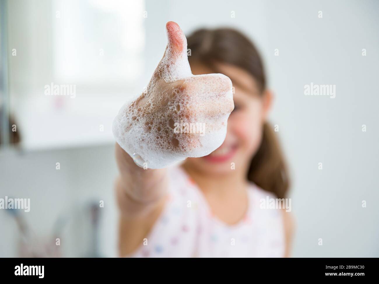 Little girl washing hands with water and soap in bathroom. Kid showing ...