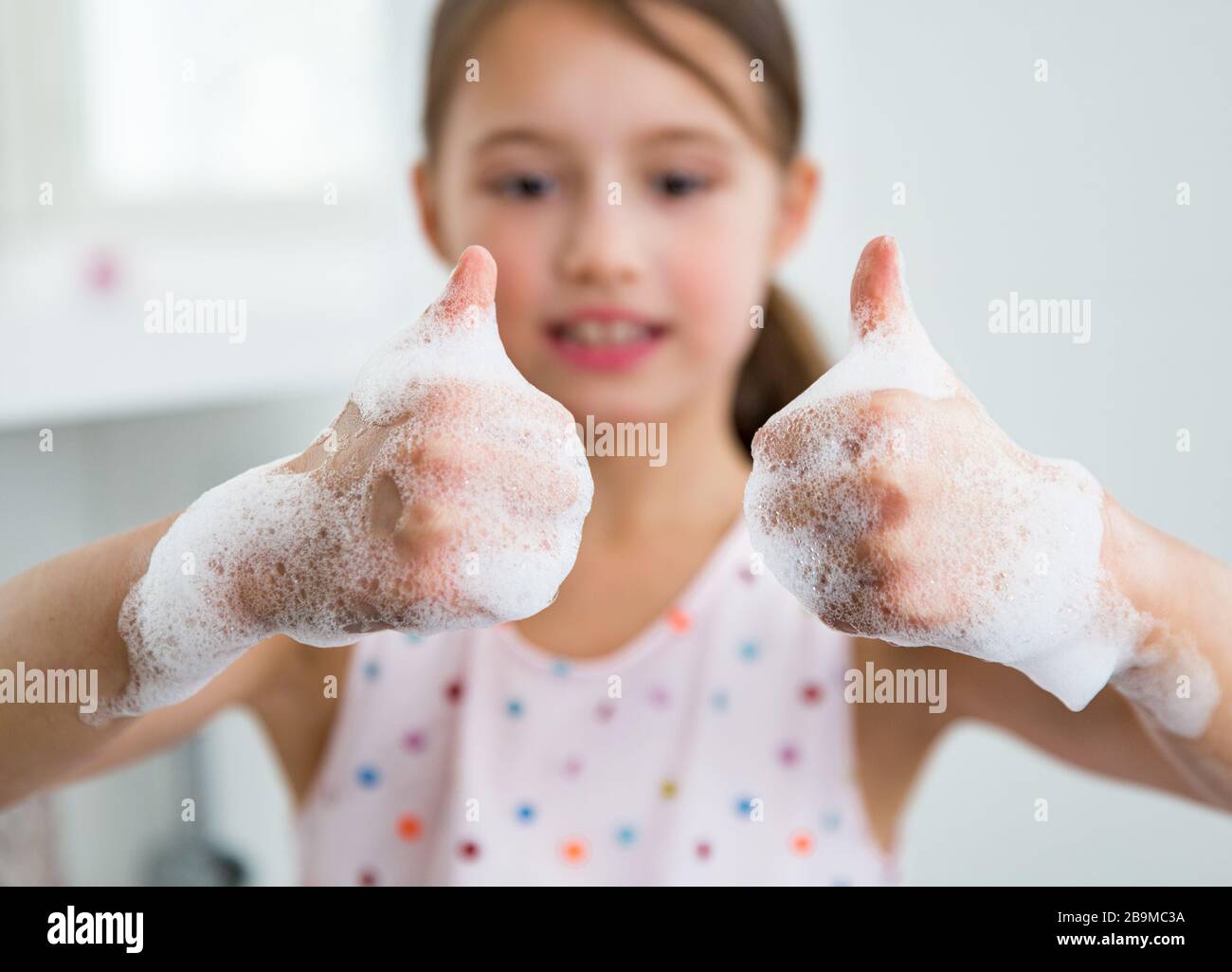 Little girl washing hands with water and soap in bathroom. Kid showing ...