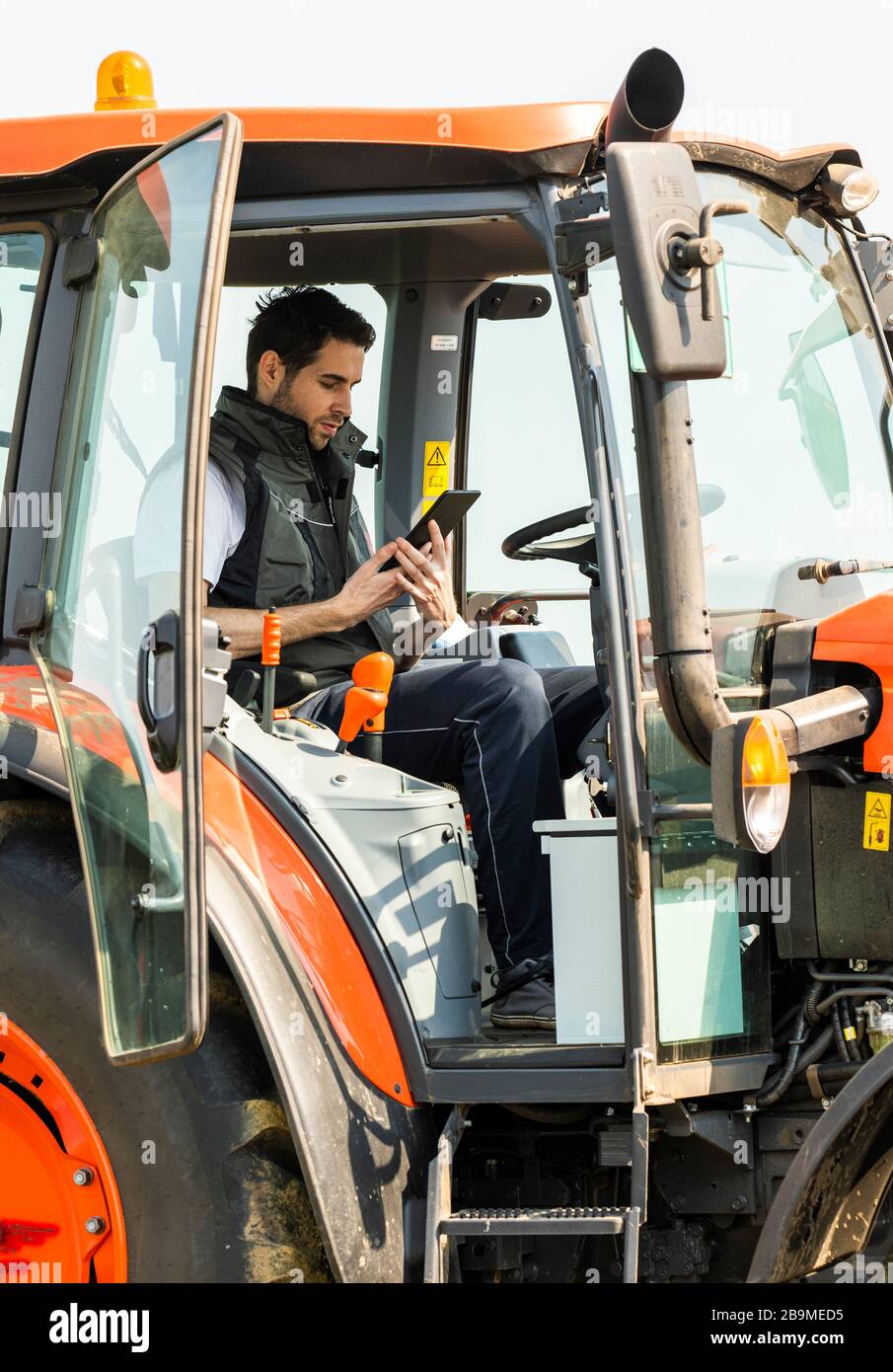 Male Agricultural Worker On tractor Using Digital Tablet Stock Photo ...
