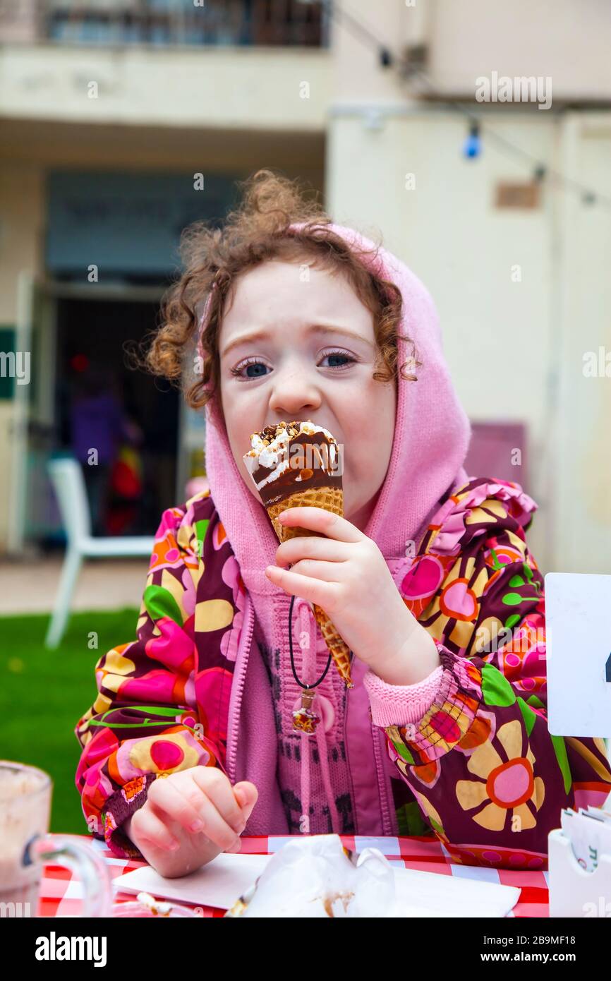 Redhead little girl eating ice cream with unusual face expression Stock ...