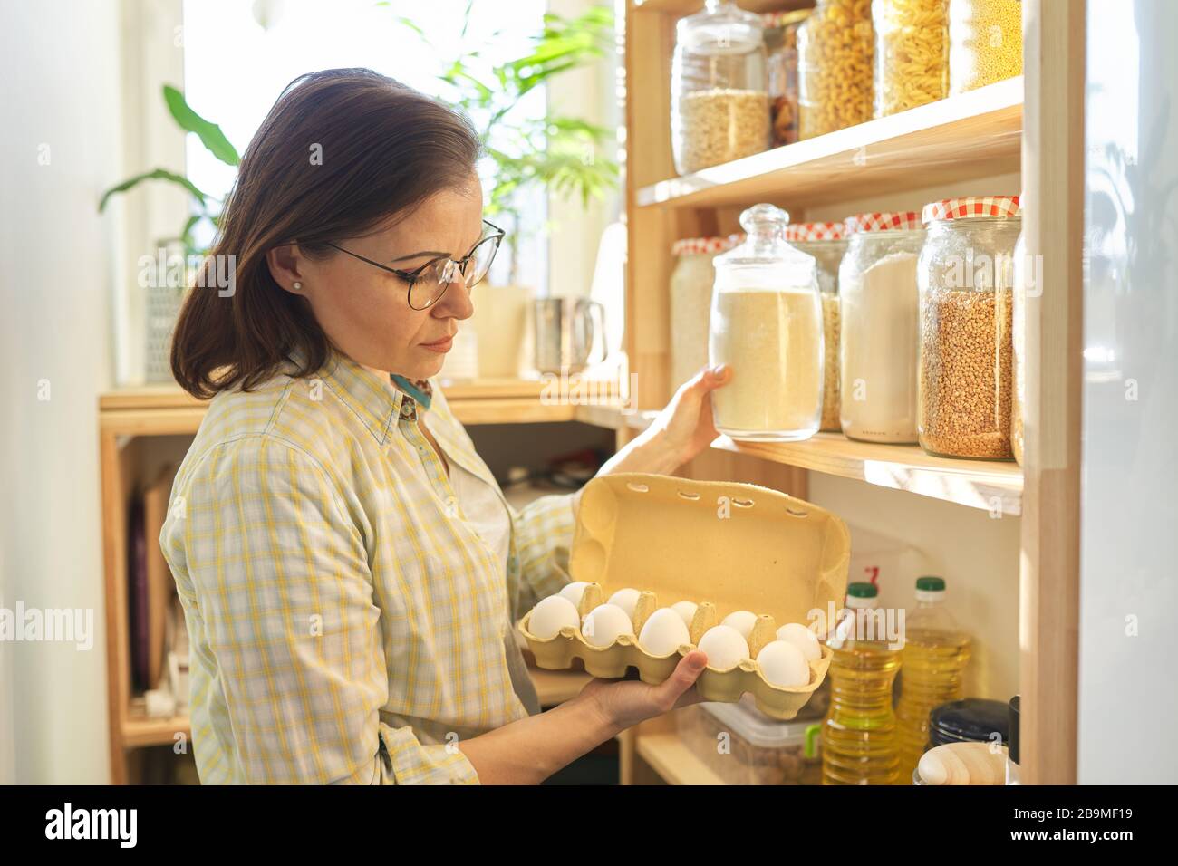 Woman in pantry taking products, eggs. Food storage, cooking at home ...