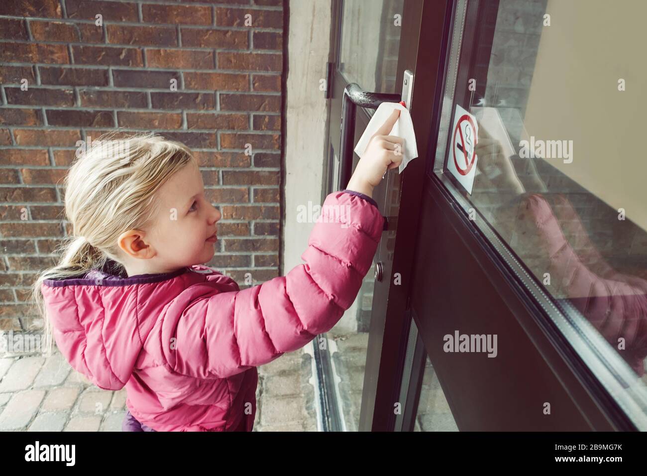 Caucasian girl pushing elevator button with disinfecting wet wipe ...