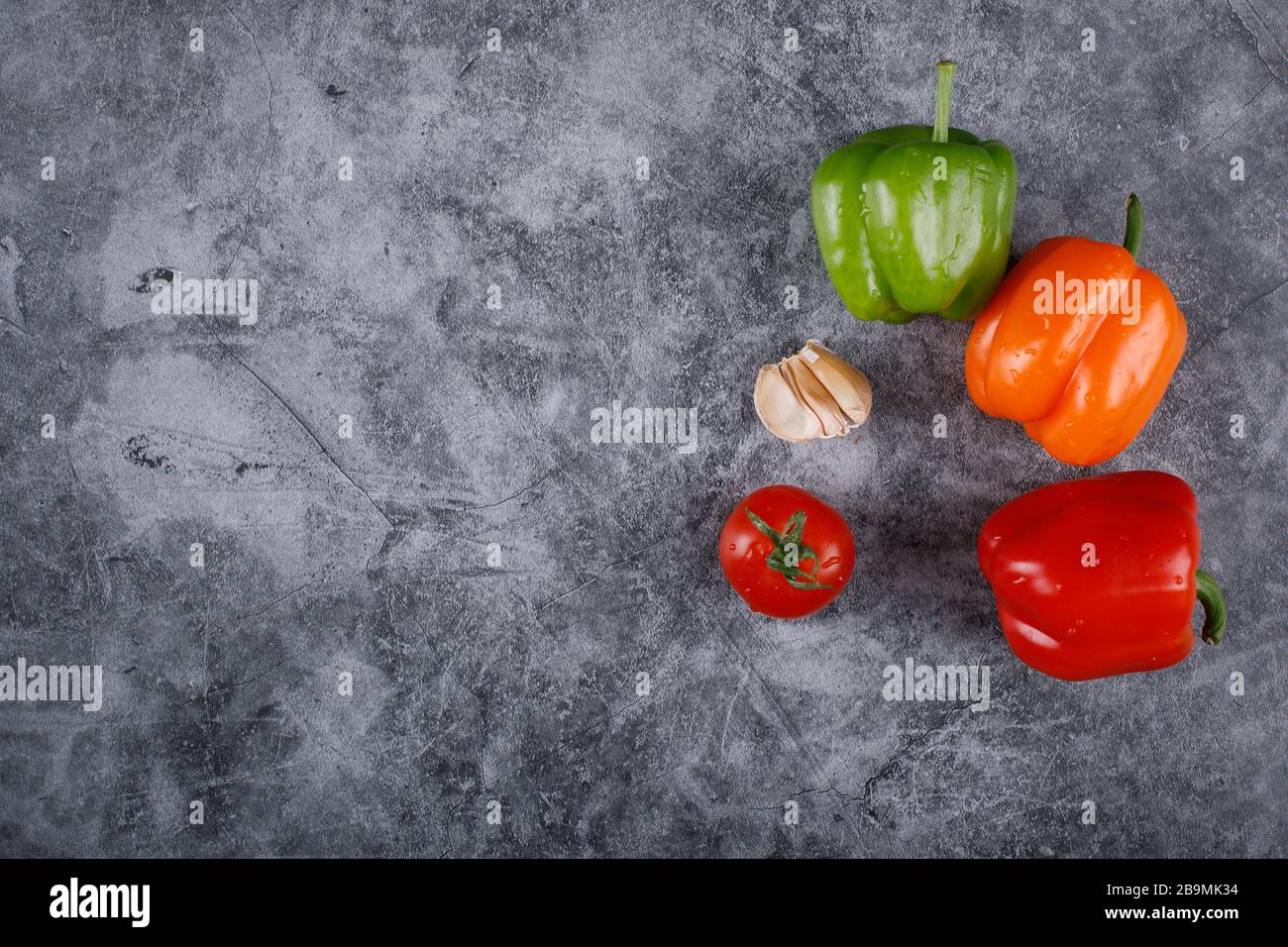 Colorful peppers, garlic and tomato on the right corner of a blue ...
