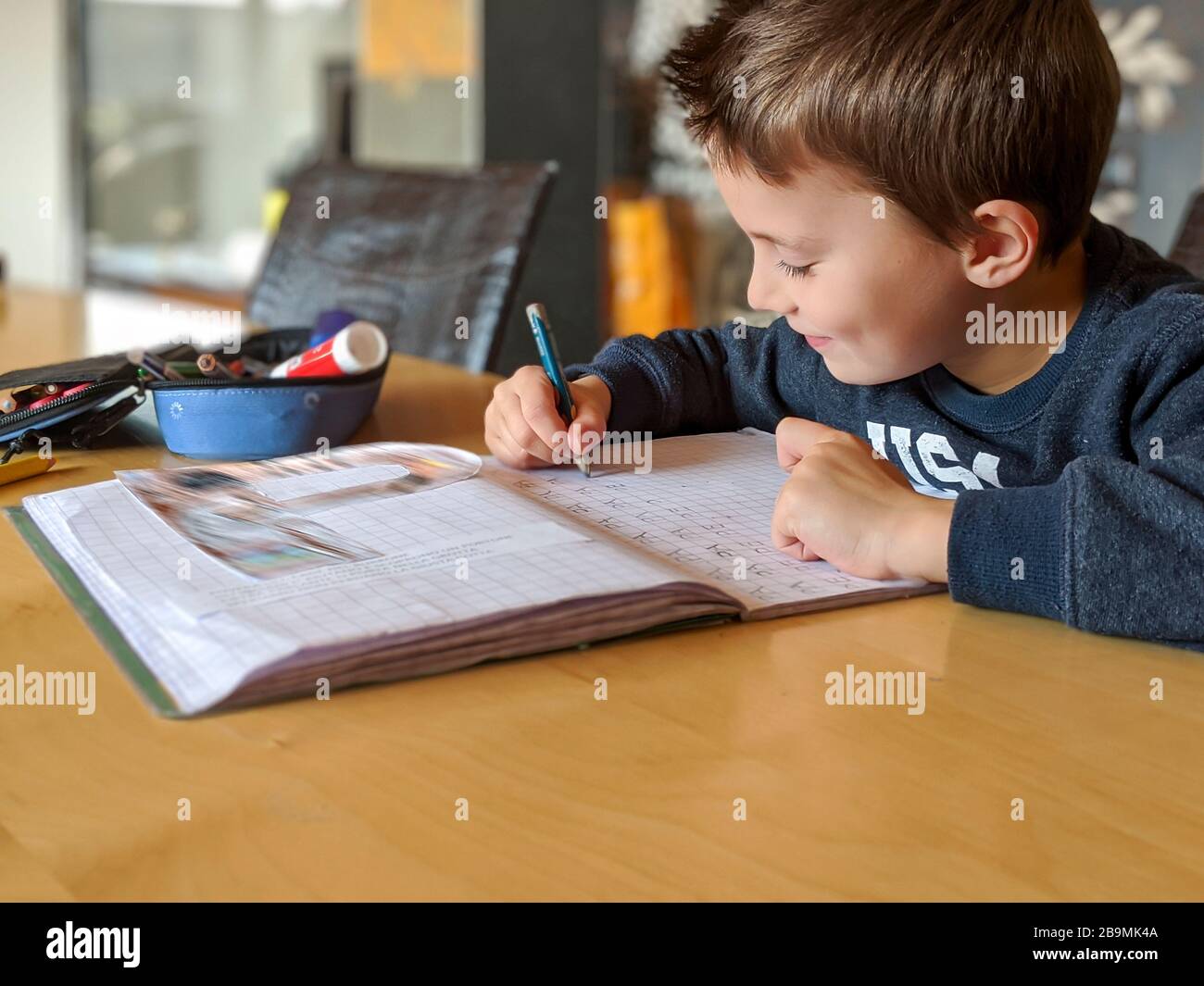 Portrait of diligent little child writing carefully sitting at desk and ...