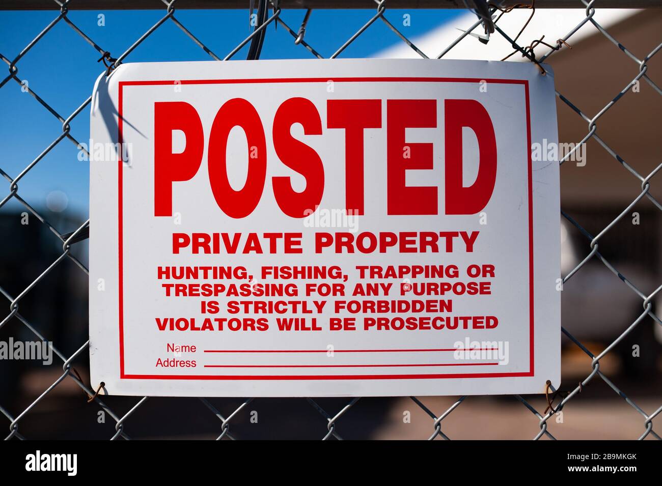 Posted private property sign warning trespassers on a chain link fence ...
