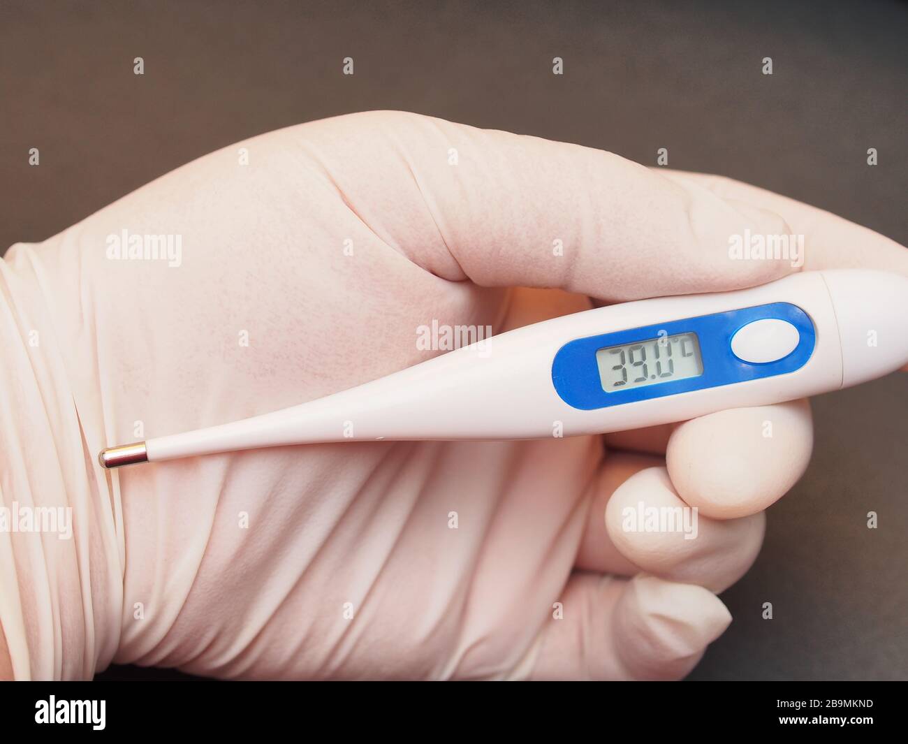 The electronic thermometer is held by a hand in a medical rubber glove ...