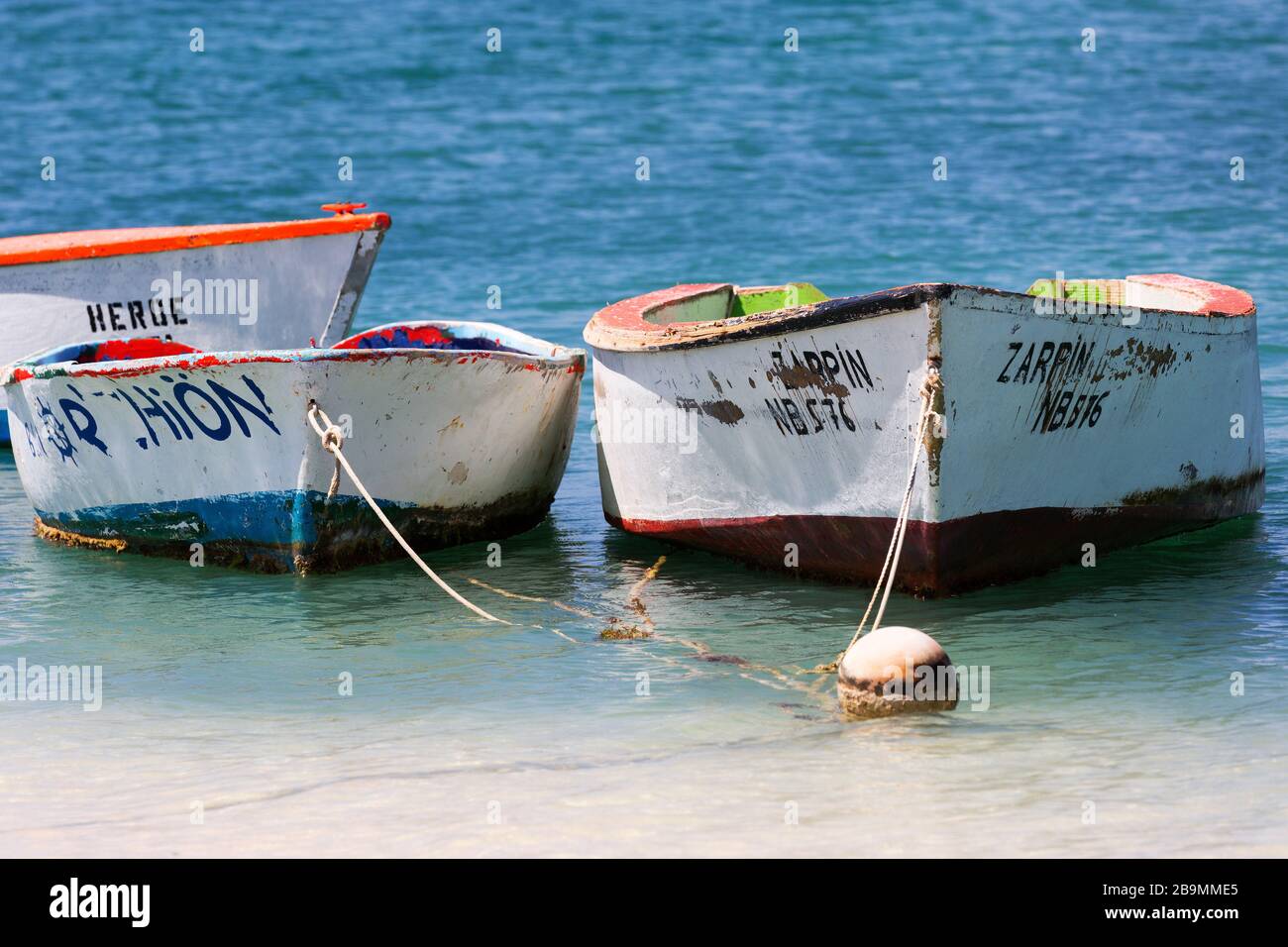 Three colorful row boats float amidstthe calm waters of Lac Bay ...