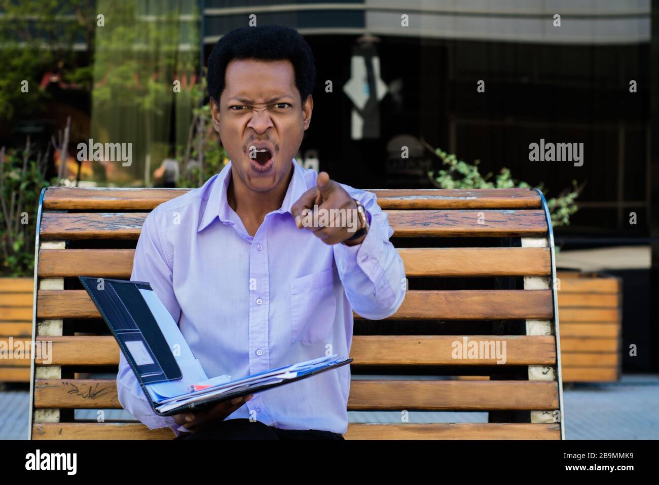 Professional young businessman angry shouting to someone outside office ...
