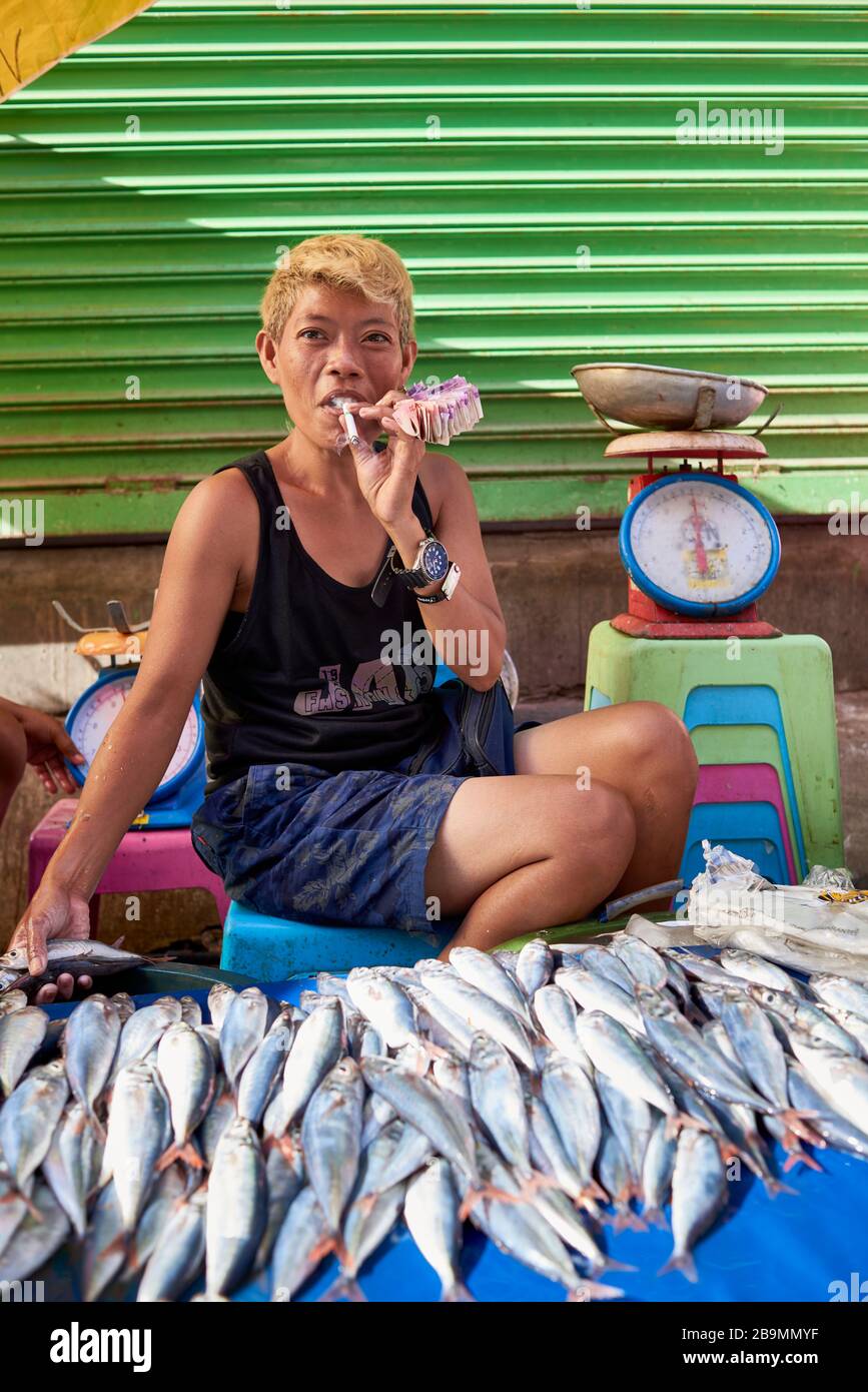 Fishmonger smoking while handling the fish in her fish stand in the ...