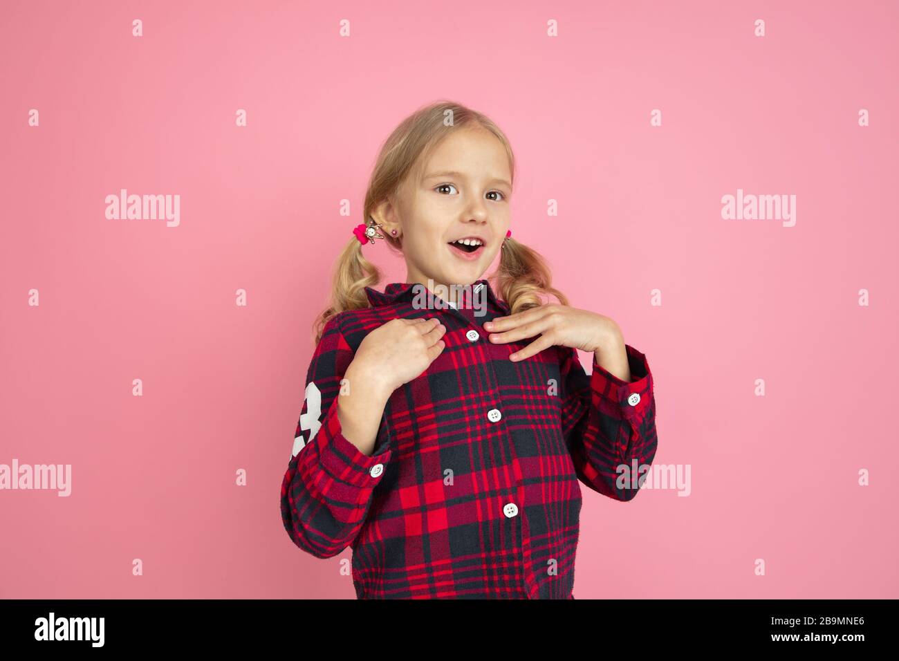 Impressed, cute. Caucasian little girl's portrait on pink studio ...