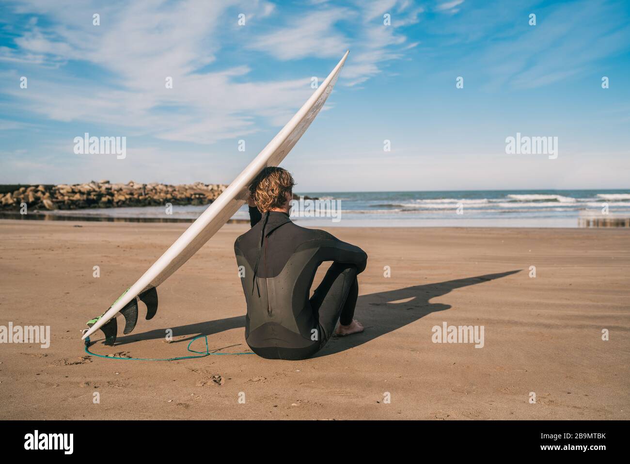 Young man sitting on beach by surfboard hi-res stock photography and ...