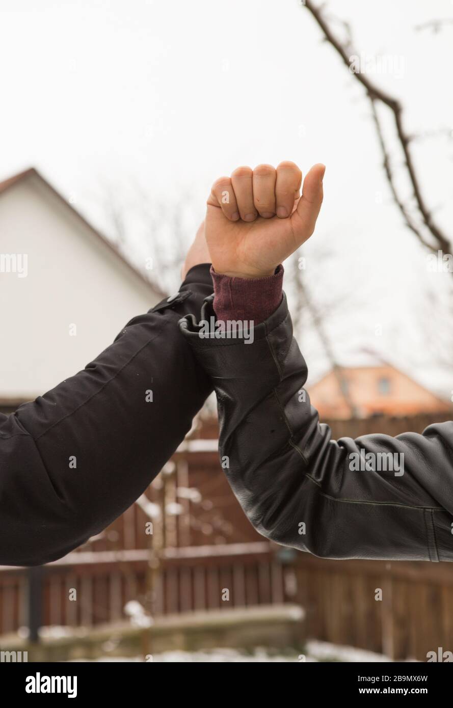 Friends shaking elbows outdoors. People greeting together by new style ...