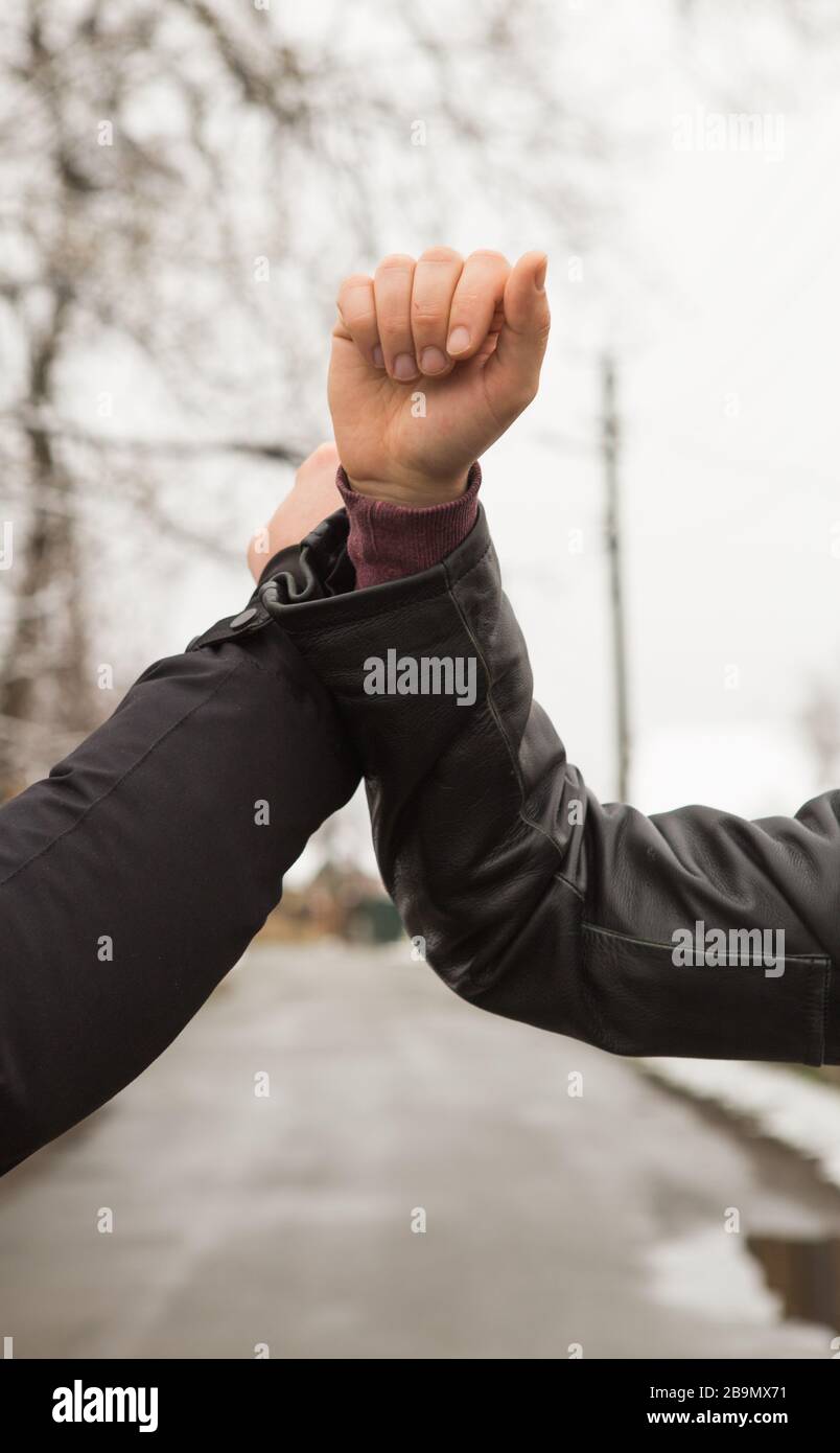 Friends shaking elbows outdoors. People greeting together by new style ...