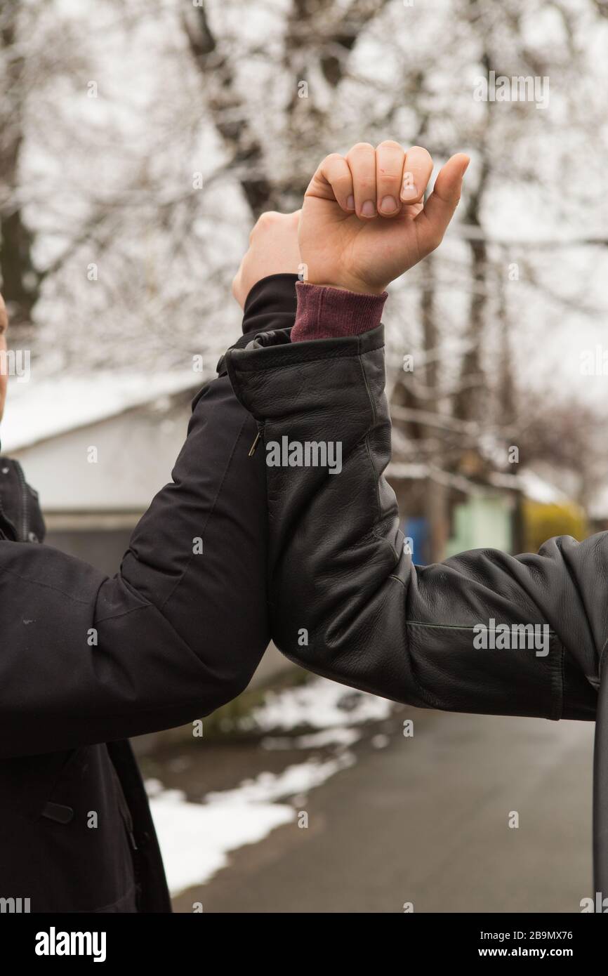 Friends shaking elbows outdoors. People greeting together by new style ...