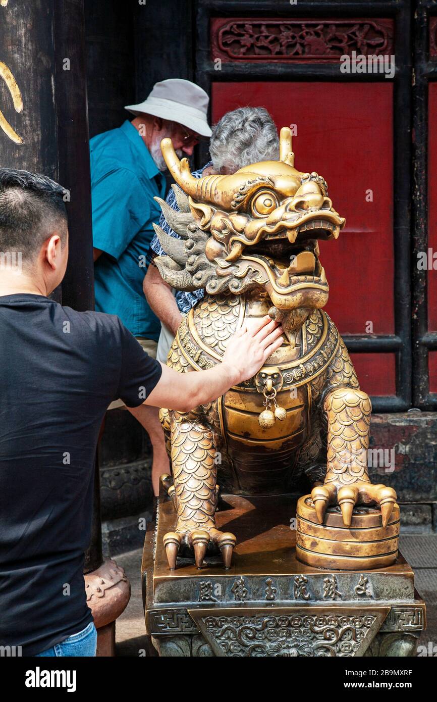 Tourists touching Chinese guardian lion in Qingyang Palace Buddhist ...