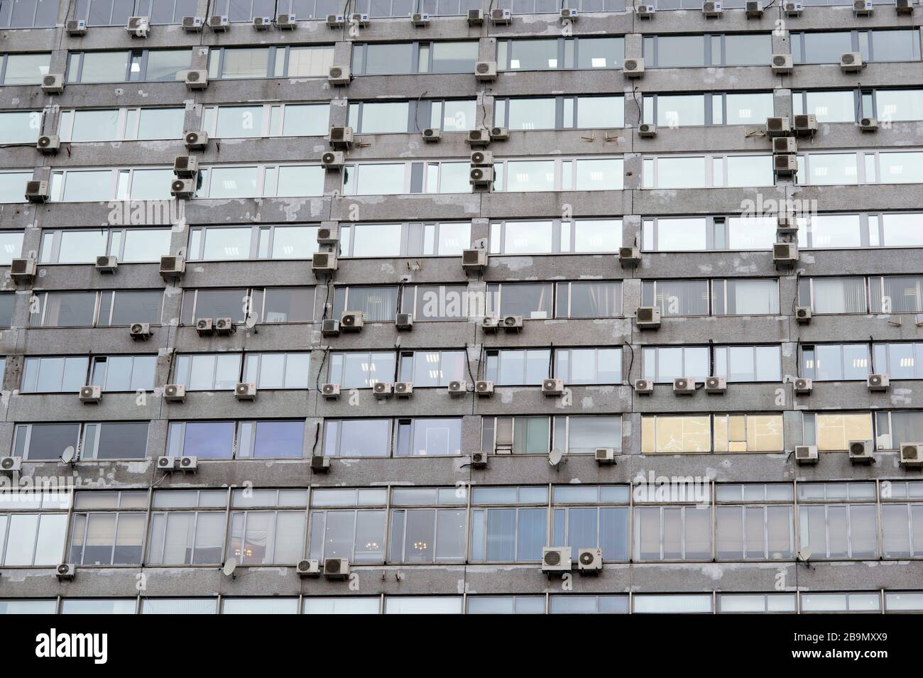 The wall of a large gray office building is studded with air ...