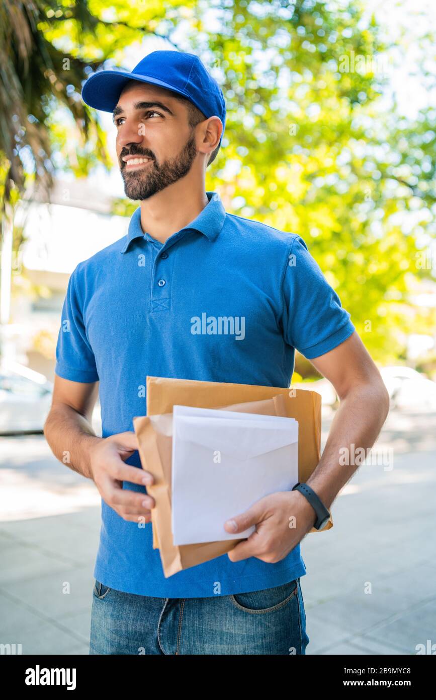Close-up of a postman carrying packages and letters outdoors in the ...