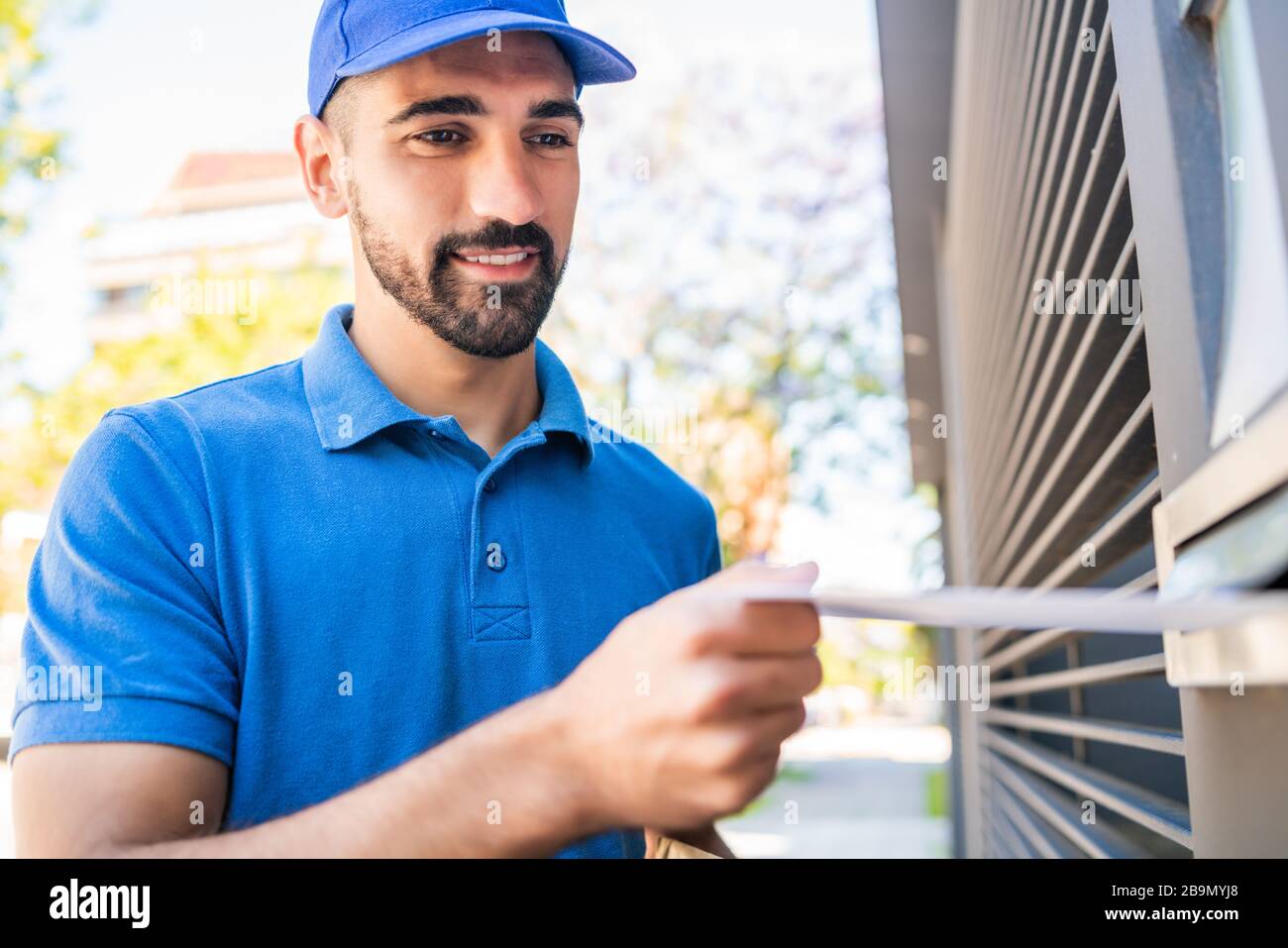 Close-up of a postman putting a letter in a house mailbox. Delivery ...