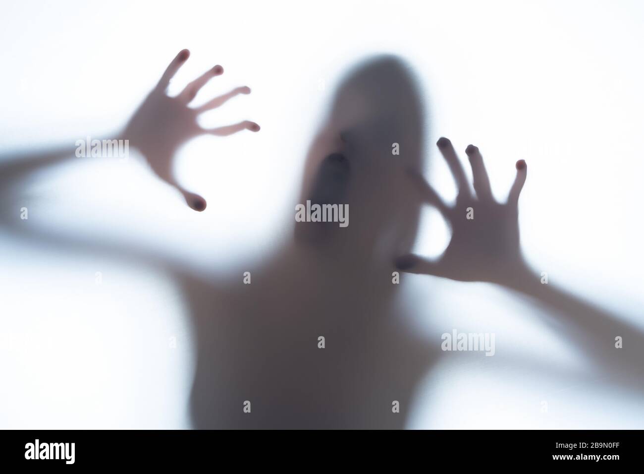 Blurred silhouette shadow of a terrorific body shape behind a white ...