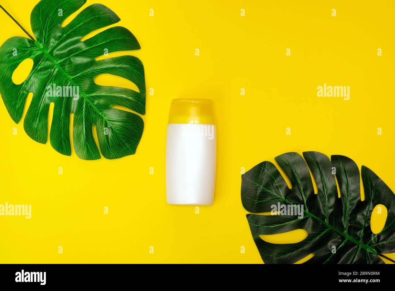 Sunscreen among green palm leaves on a yellow background. Empty sun ...