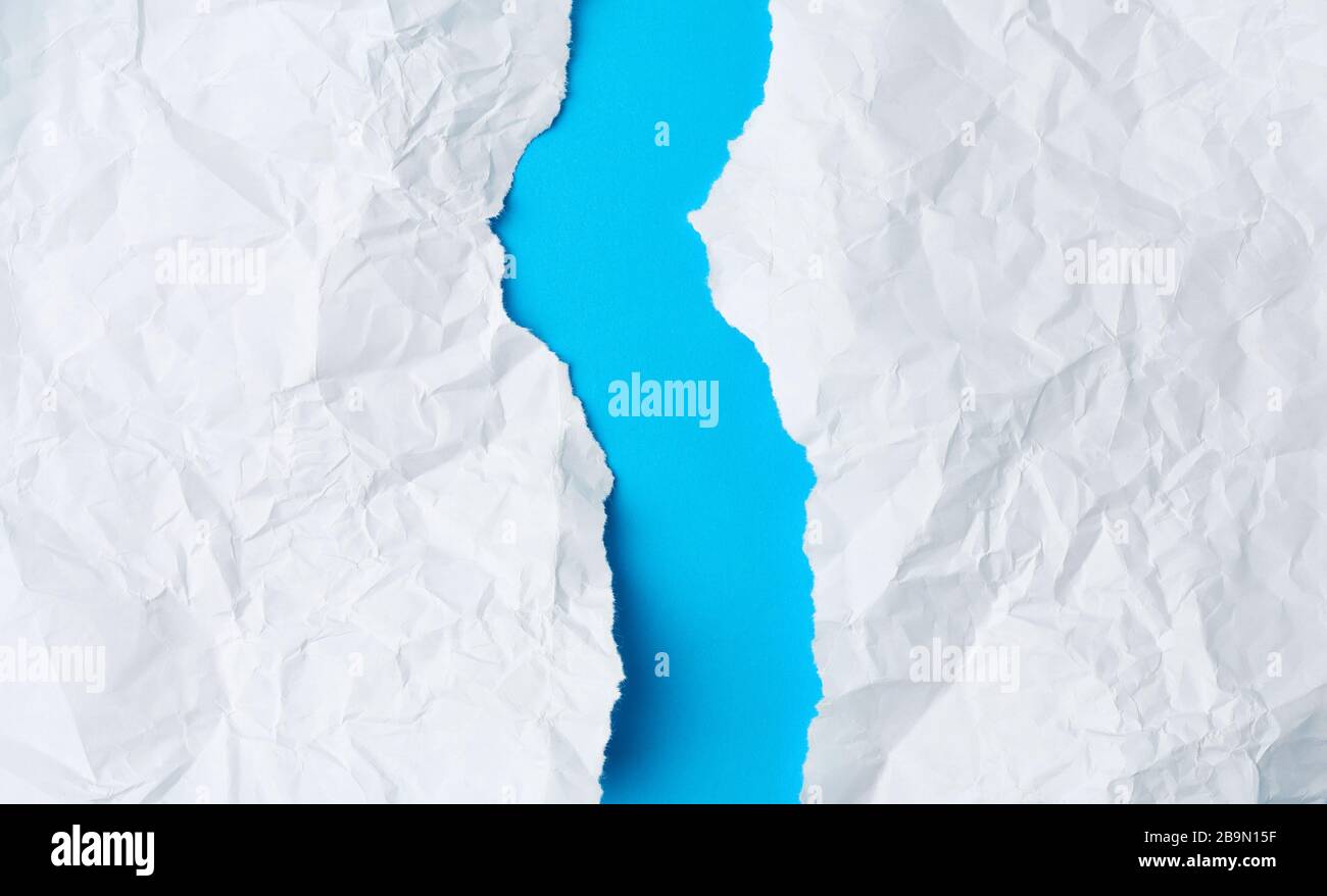 crumpled white sheet of paper torn in two on a blue background. Paper ...