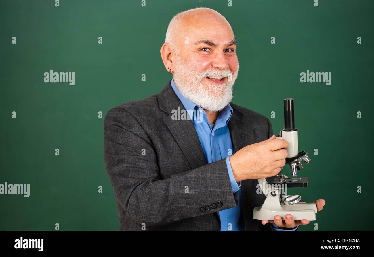 fascinating biology lesson. happy senior teacher use microscope ...