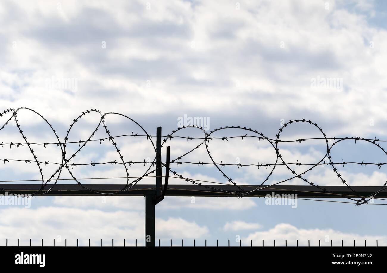 Coiled barbed wire fence and blue sky with clouds at background Stock ...