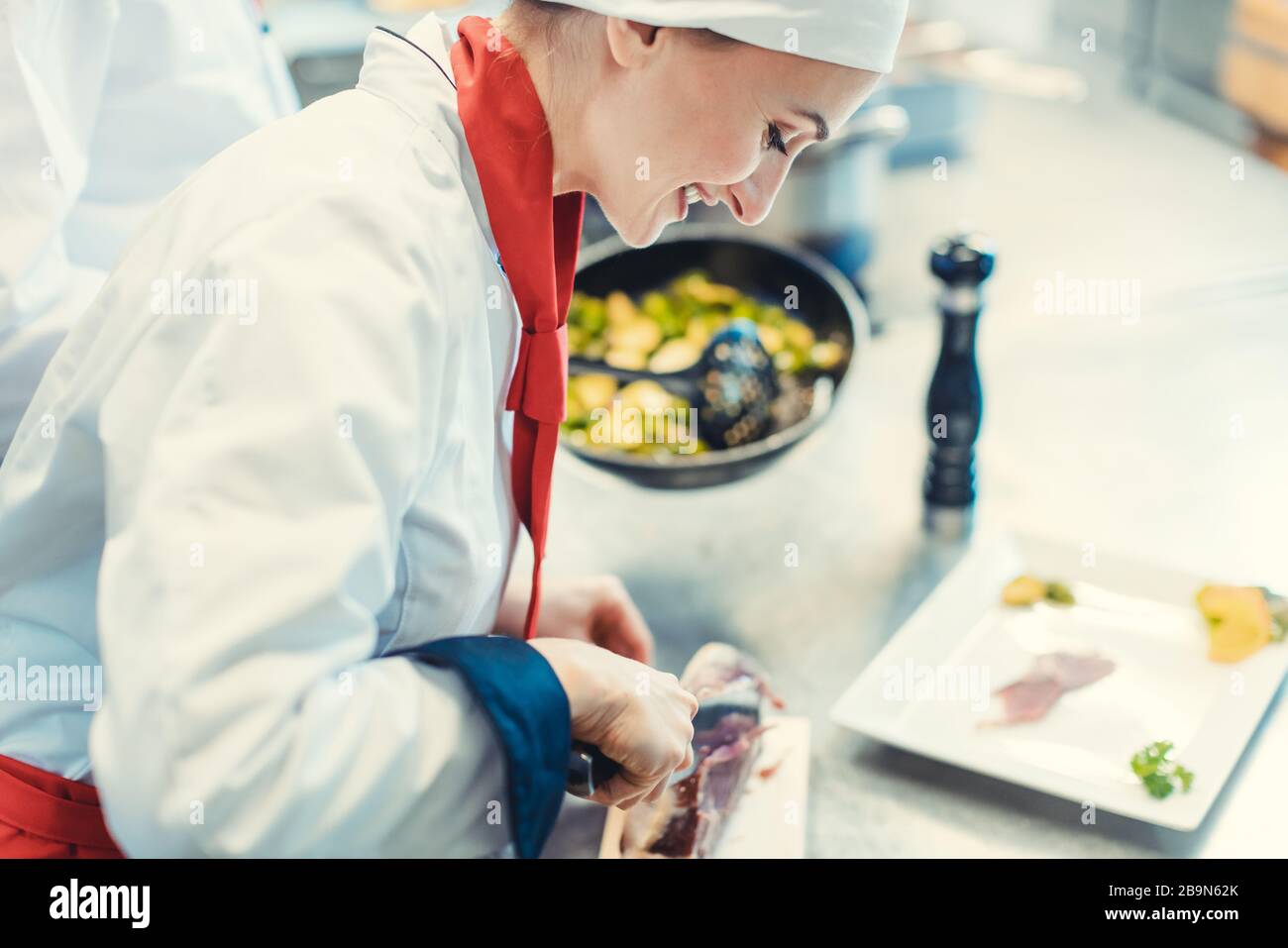 Chef cook in fancy restaurant kitchen slicing ham for a dish Stock ...