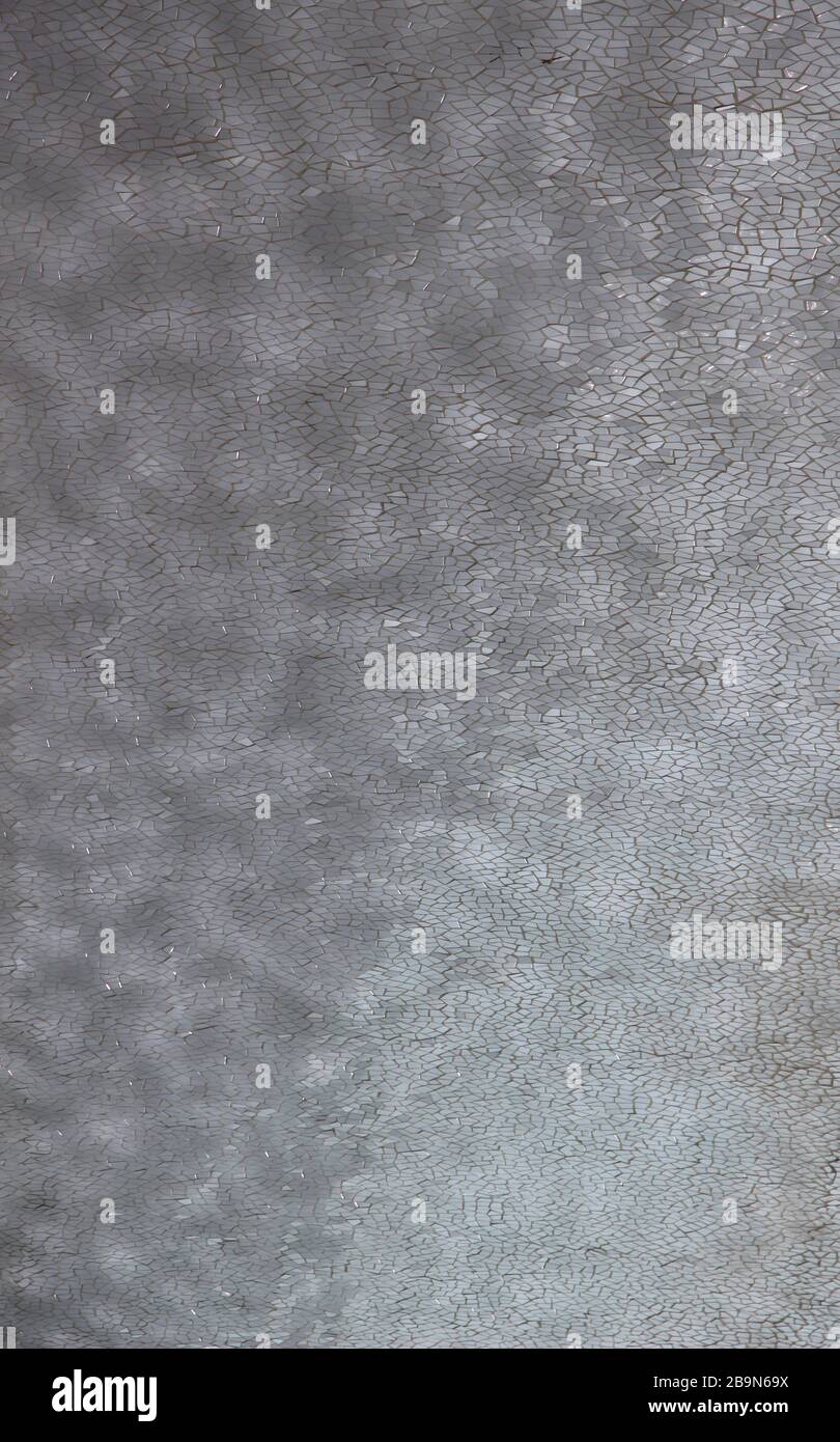 Mosaic of small grey tiles with moving water reflecting sunlight on the ...