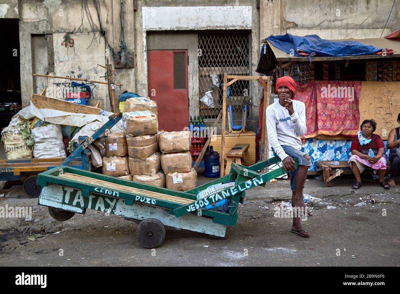 Portrait of a porter sitting on his trolley and smoking a cigarette ...