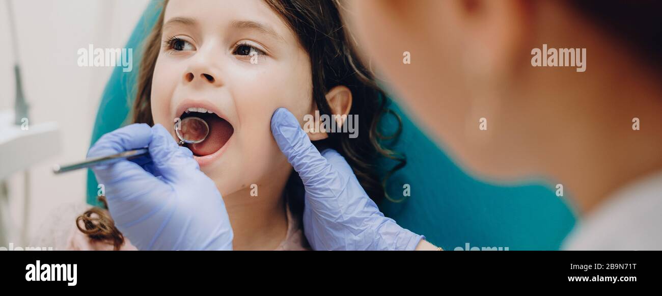 Charming curly haired caucasian girl having a teeth examination at the ...