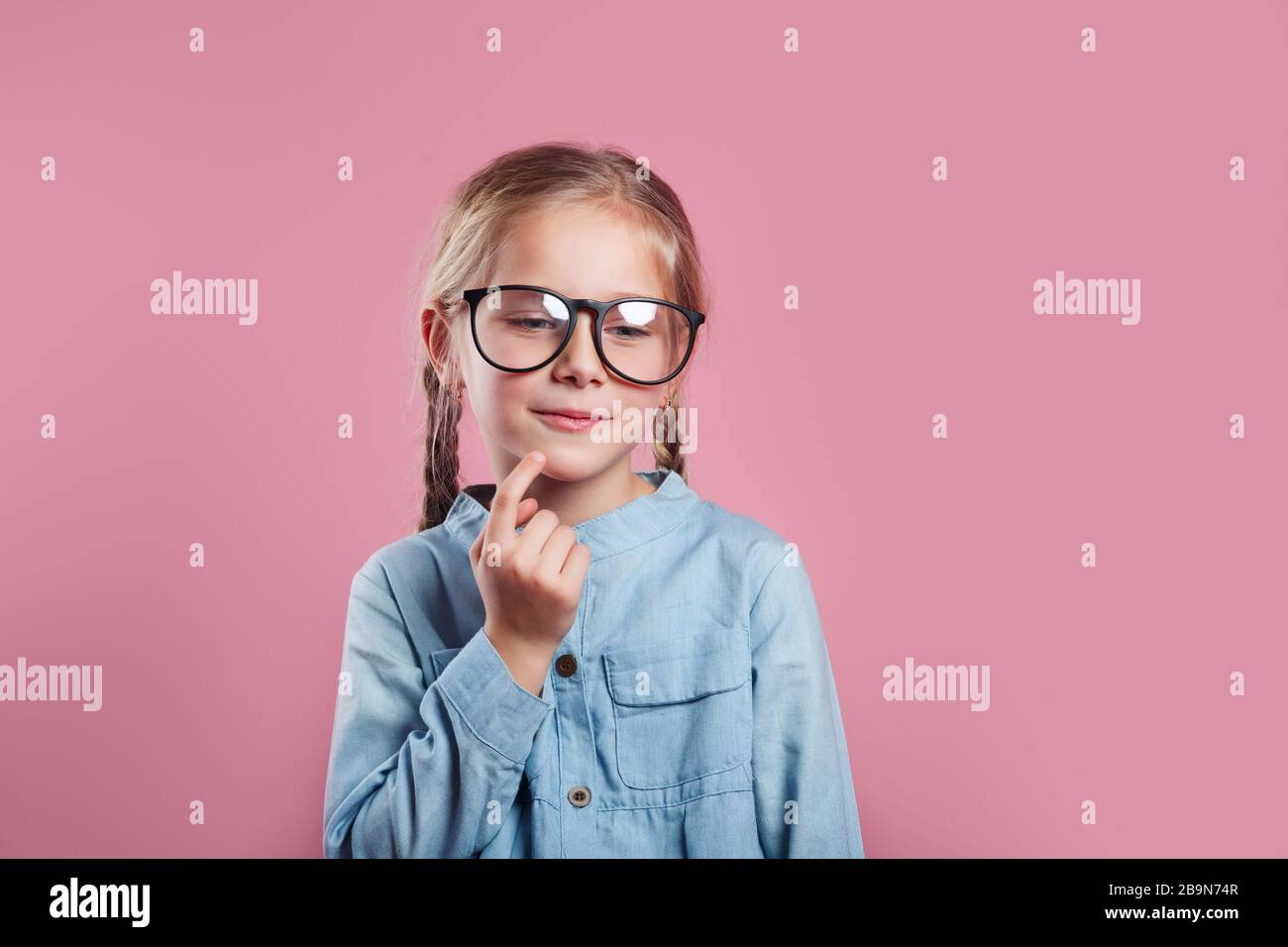 Little girl serious face thinking about question on pink background ...